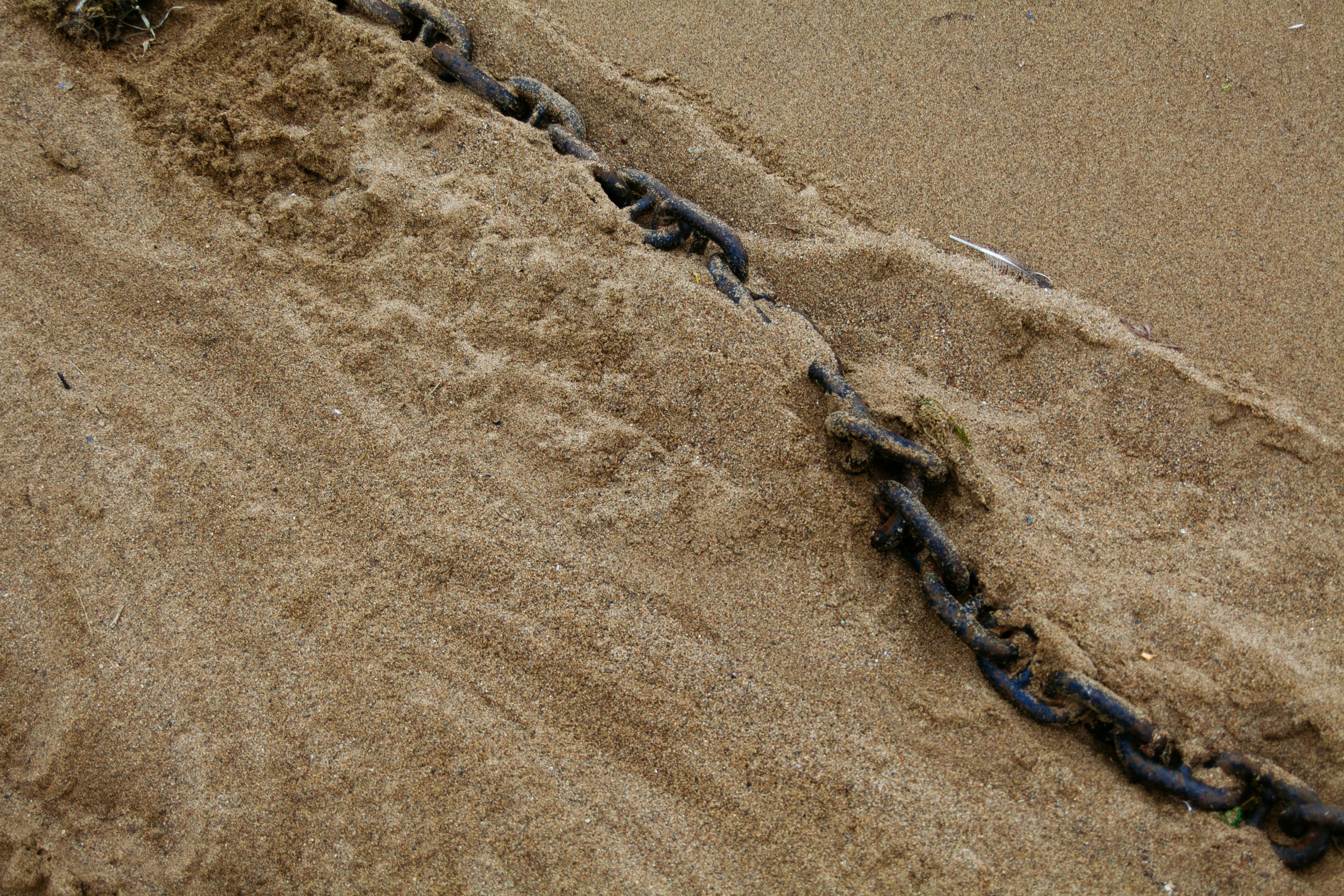 Metal chain placed on sand · Free Stock Photo