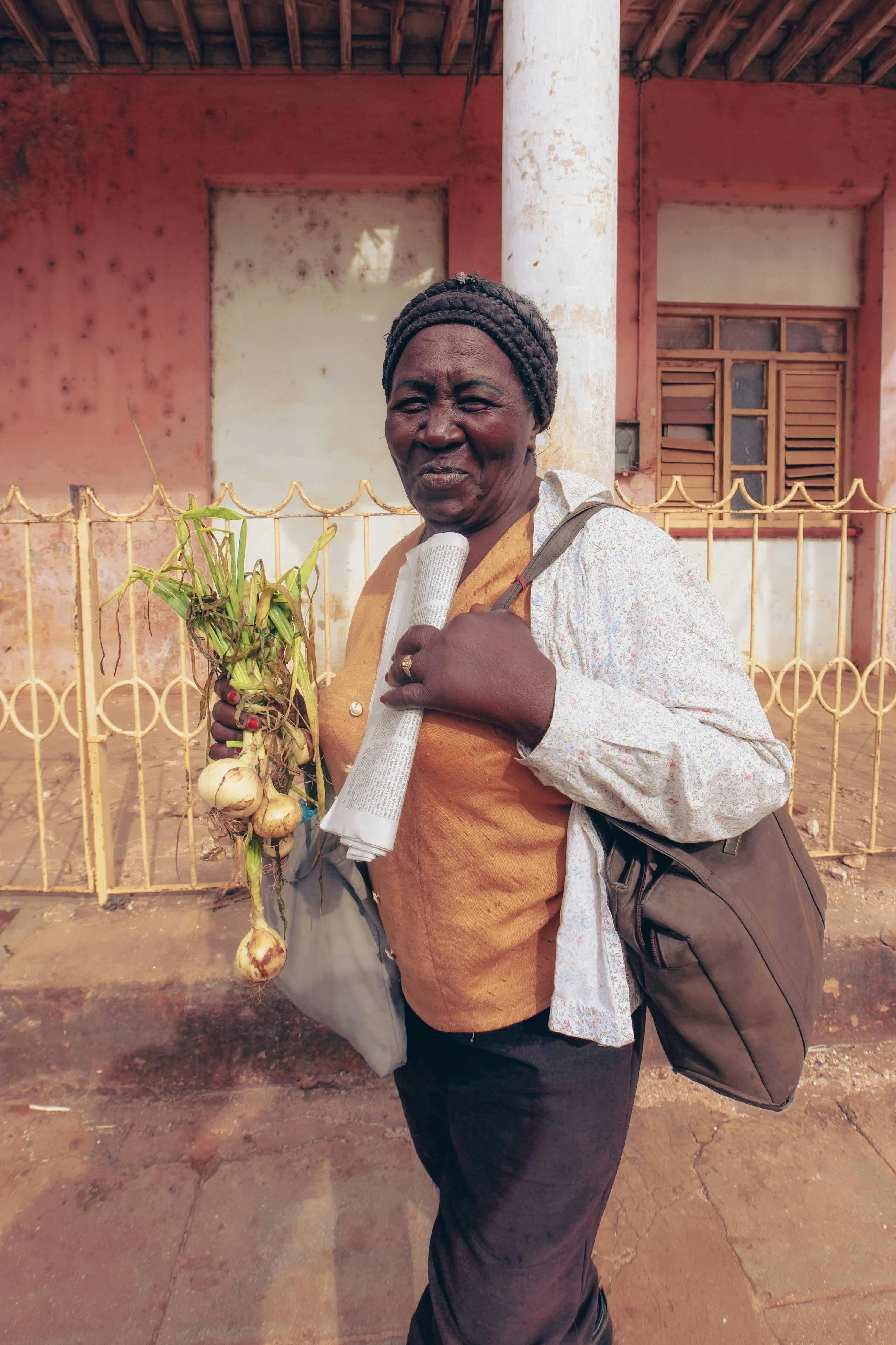 Smiling ethnic woman sitting on haunches on street near baskets with ...