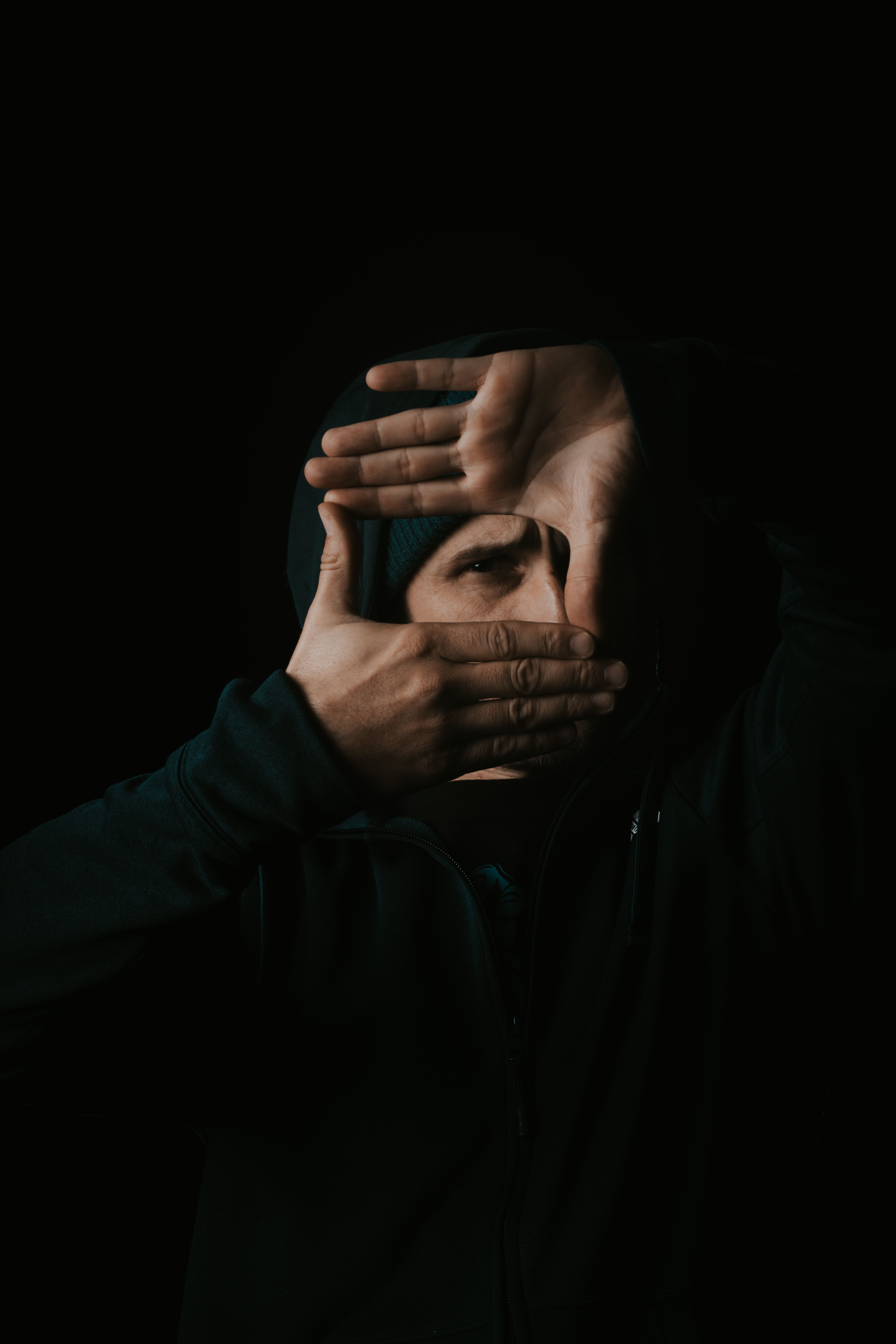 Faceless guy making frame gesture in dark studio · Free Stock Photo