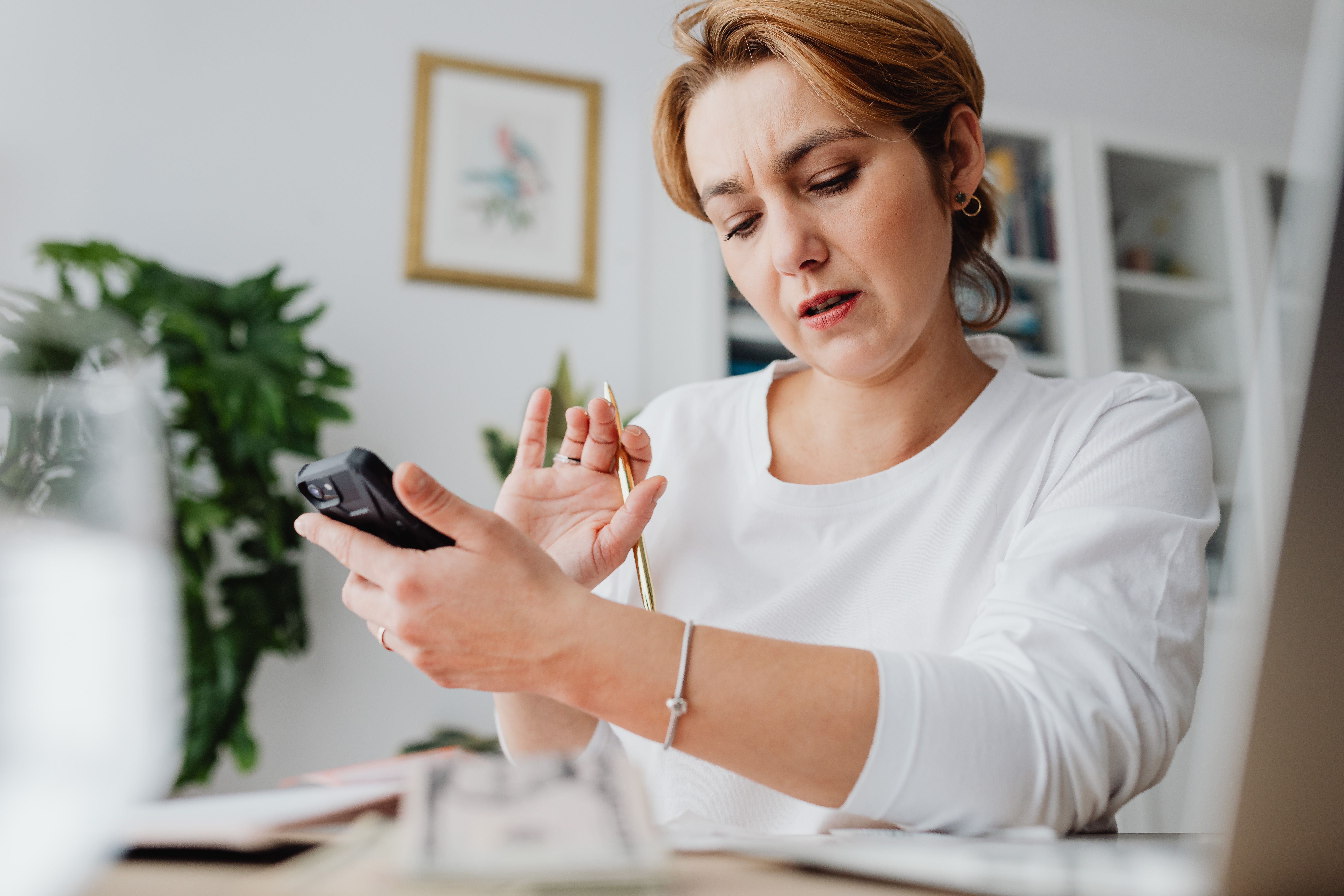 Woman at Wooden Desk Reading a Receipt · Free Stock Photo
