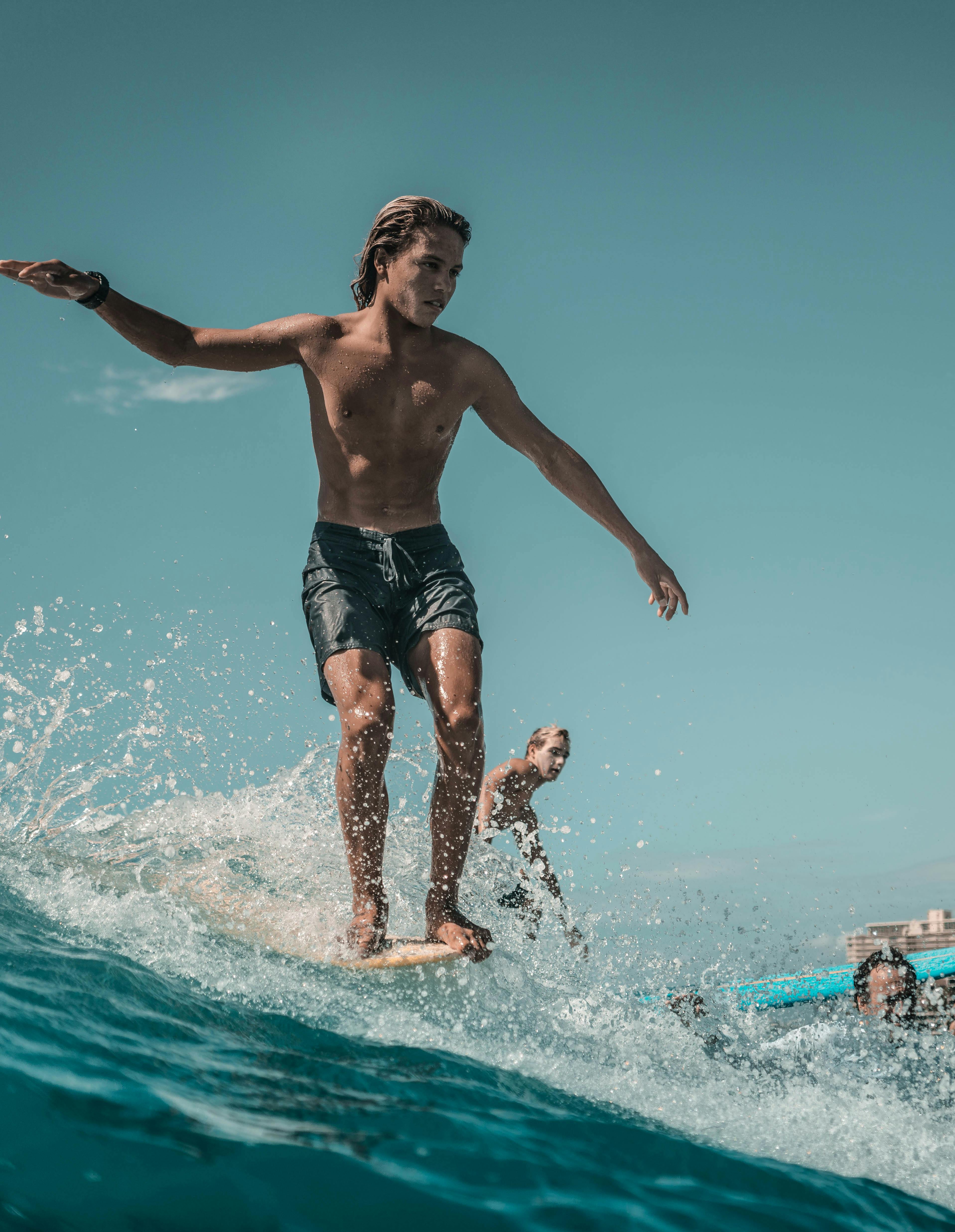Young man balancing on surfboard in ocean water · Free Stock Photo