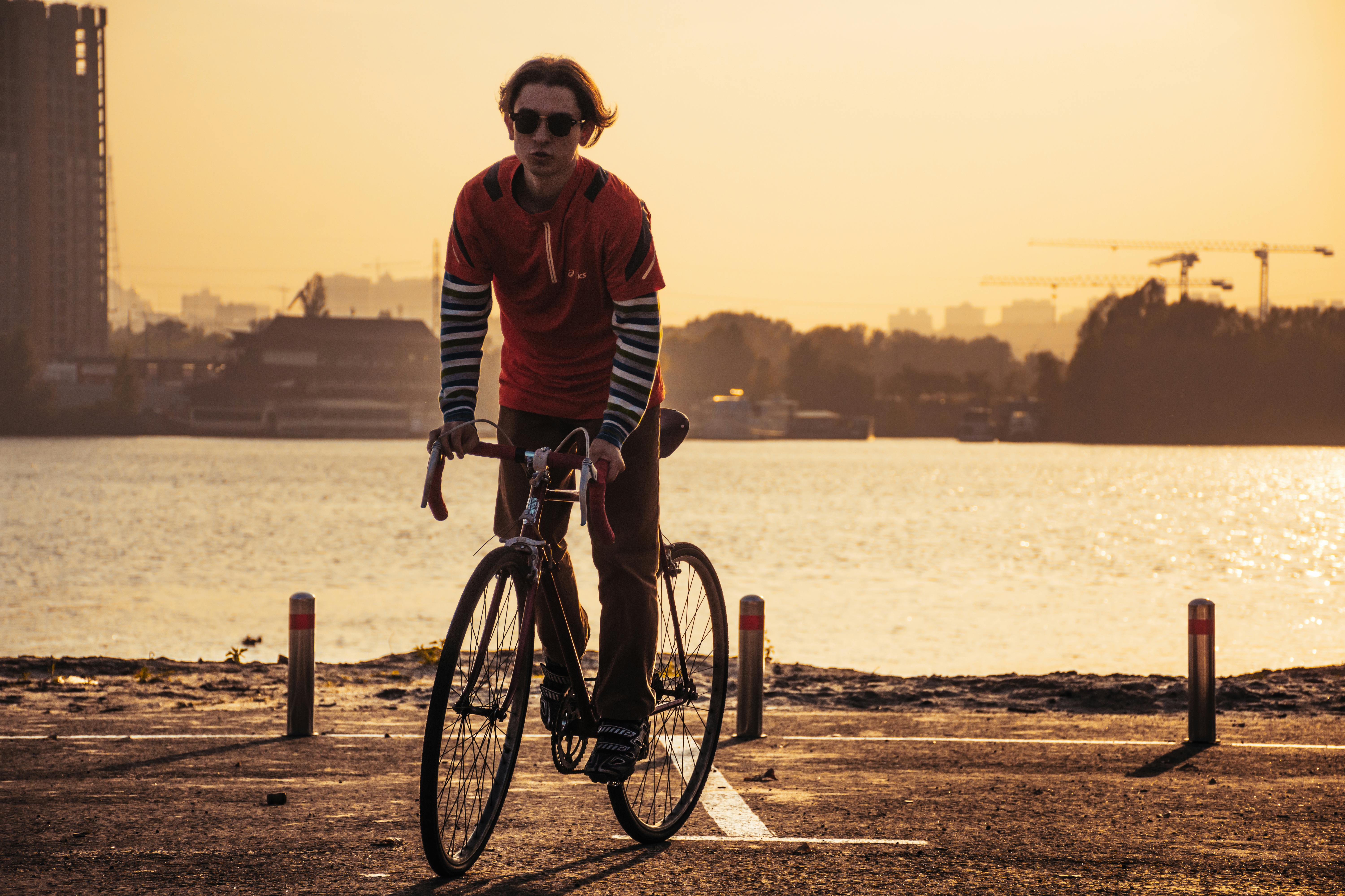 Man Riding Bike Near Lake at Dusk · Free Stock Photo