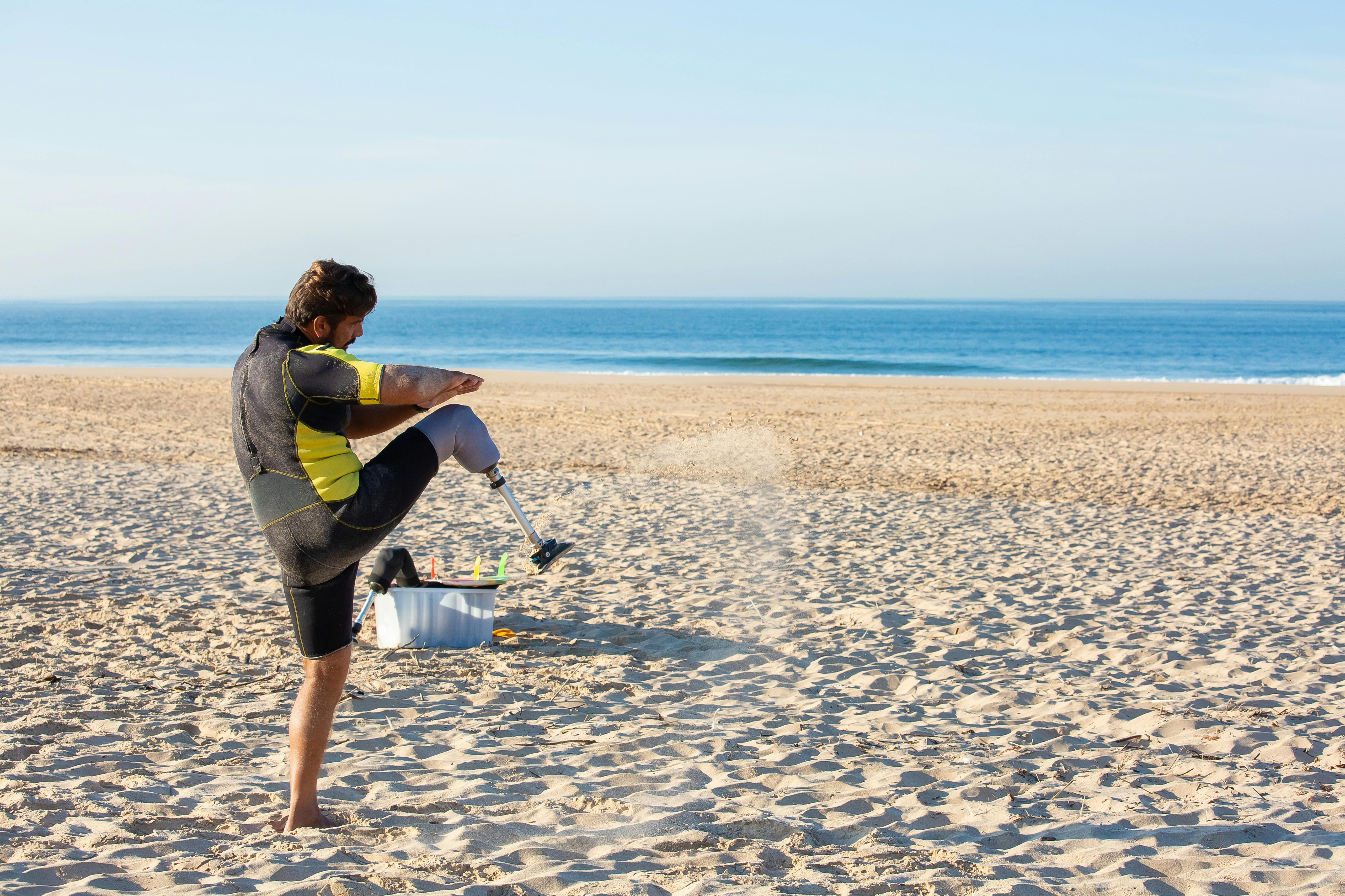 Faceless amputee sportsman performing high step exercise on beach ...
