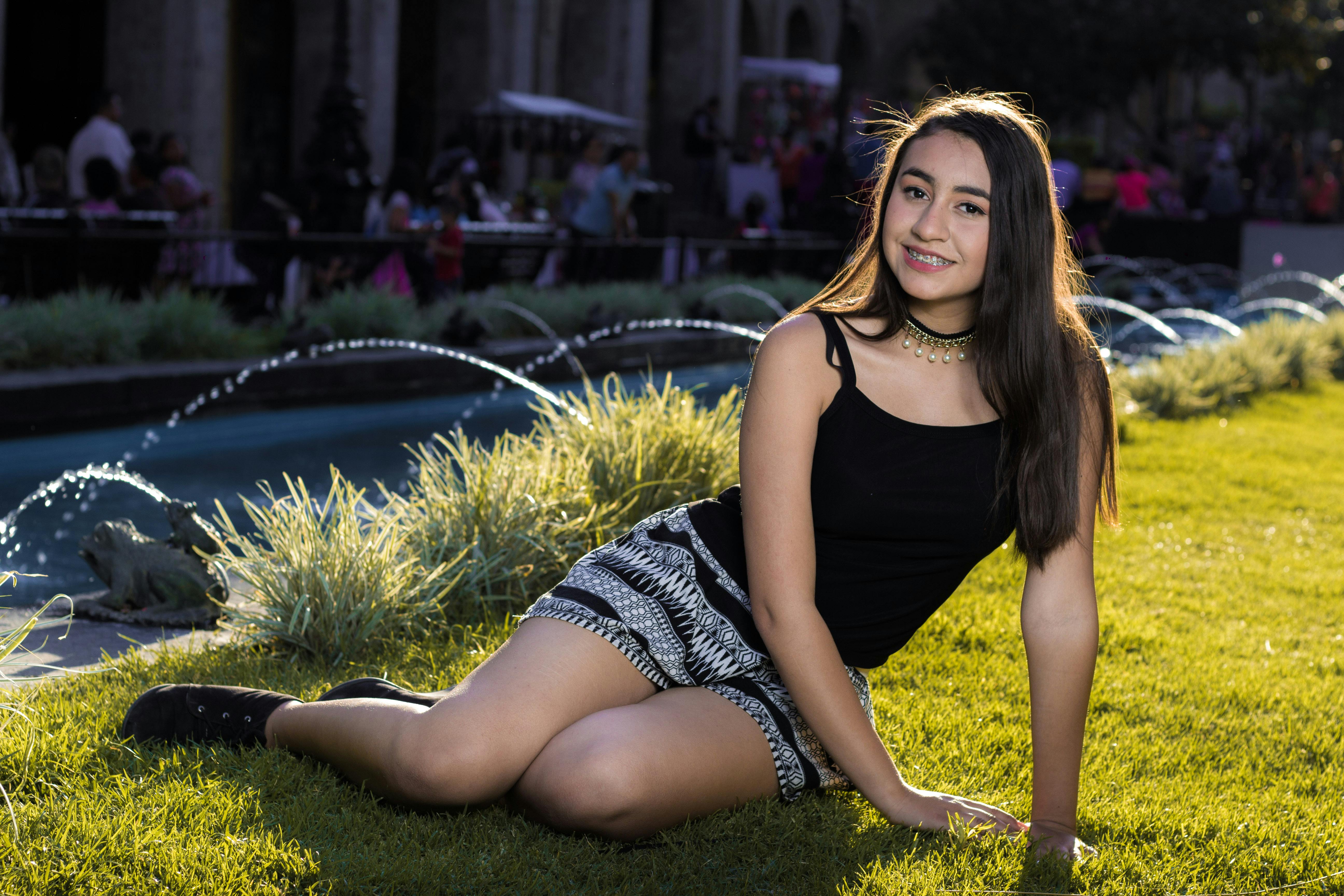 Woman in Black Tank Top and Black and White Short Sitting on the Grass ...