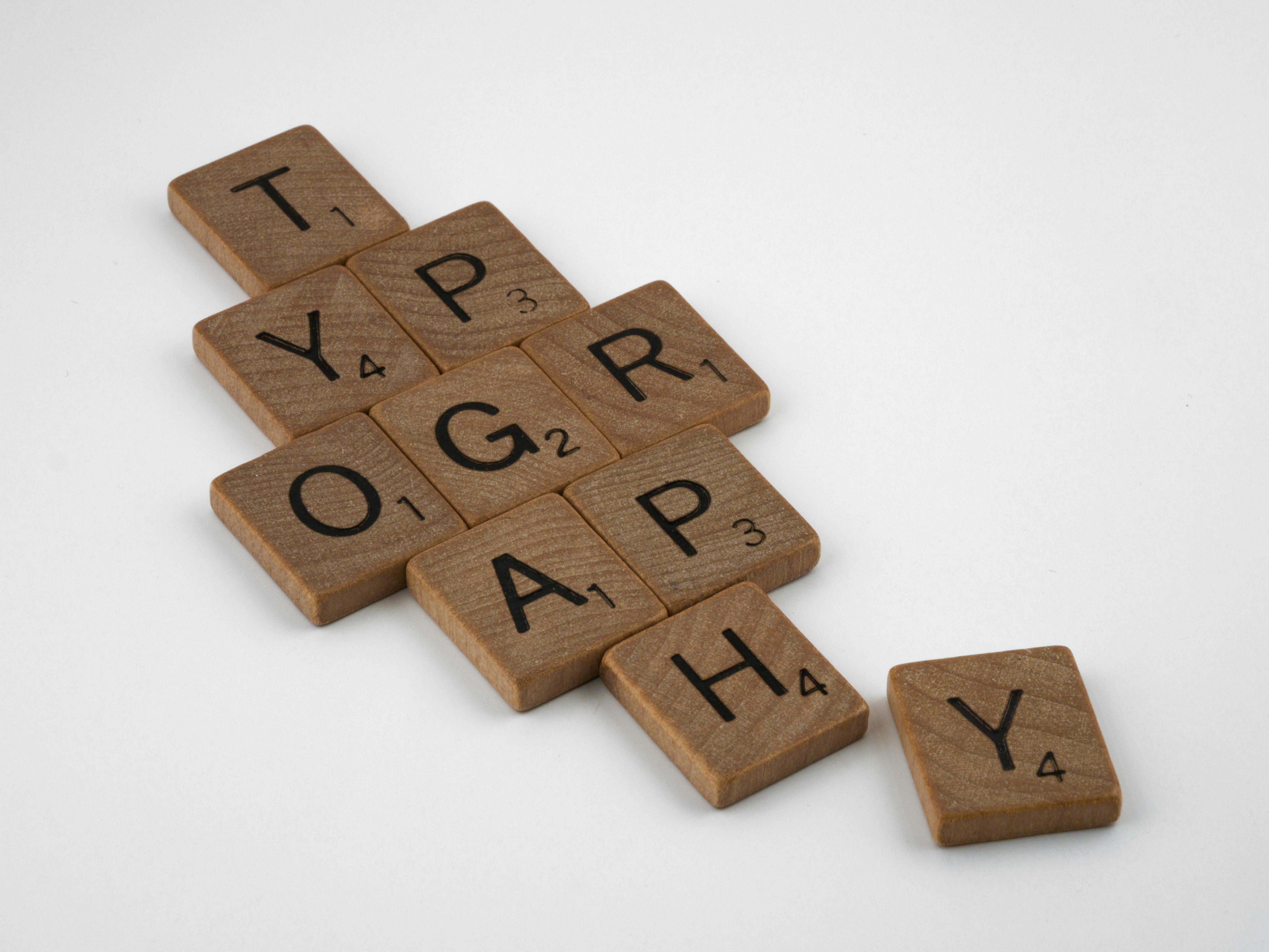 Close-Up Shot of Scrabble Tiles on White Surface · Free Stock Photo