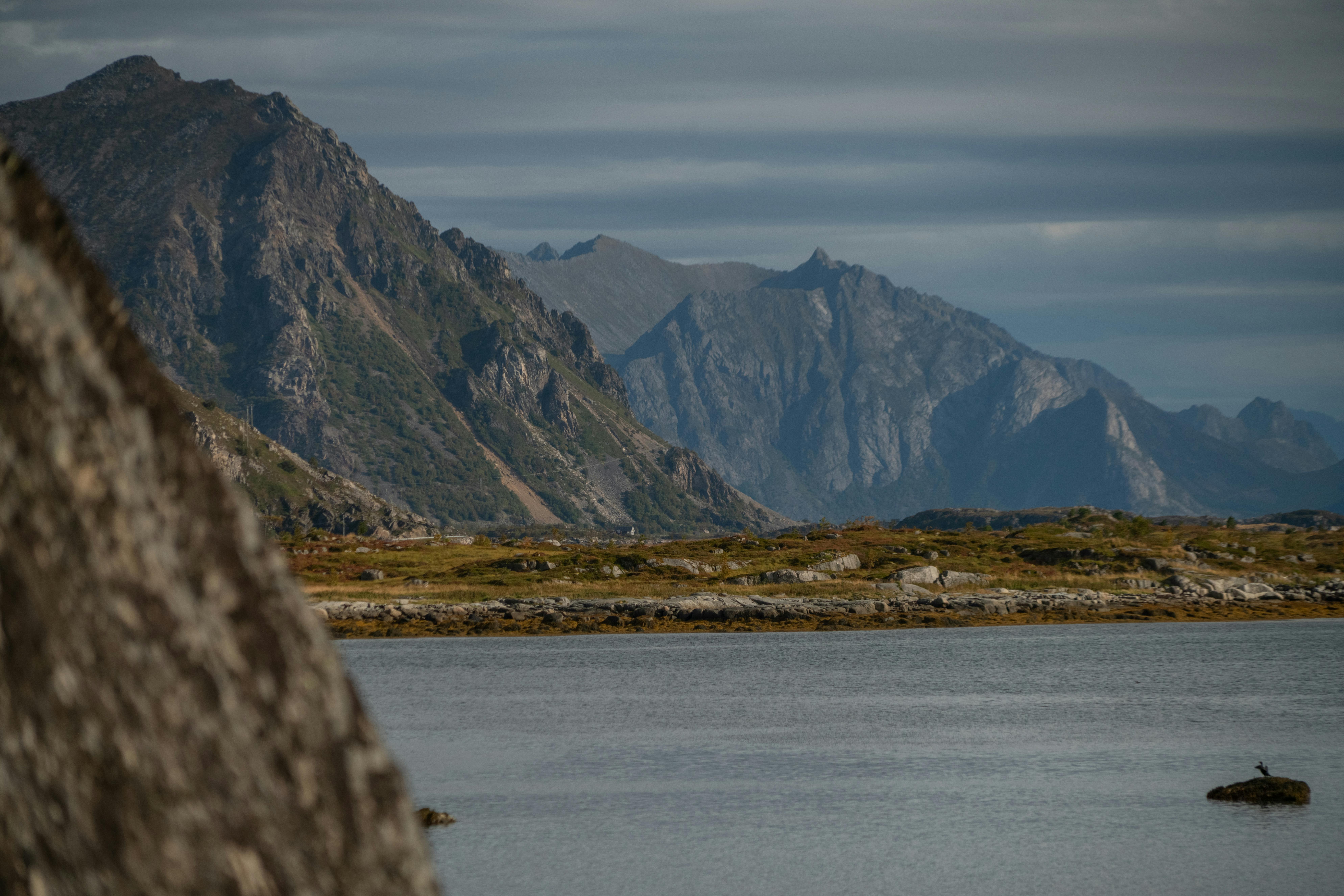 Rocky mountains near calm water in daytime · Free Stock Photo
