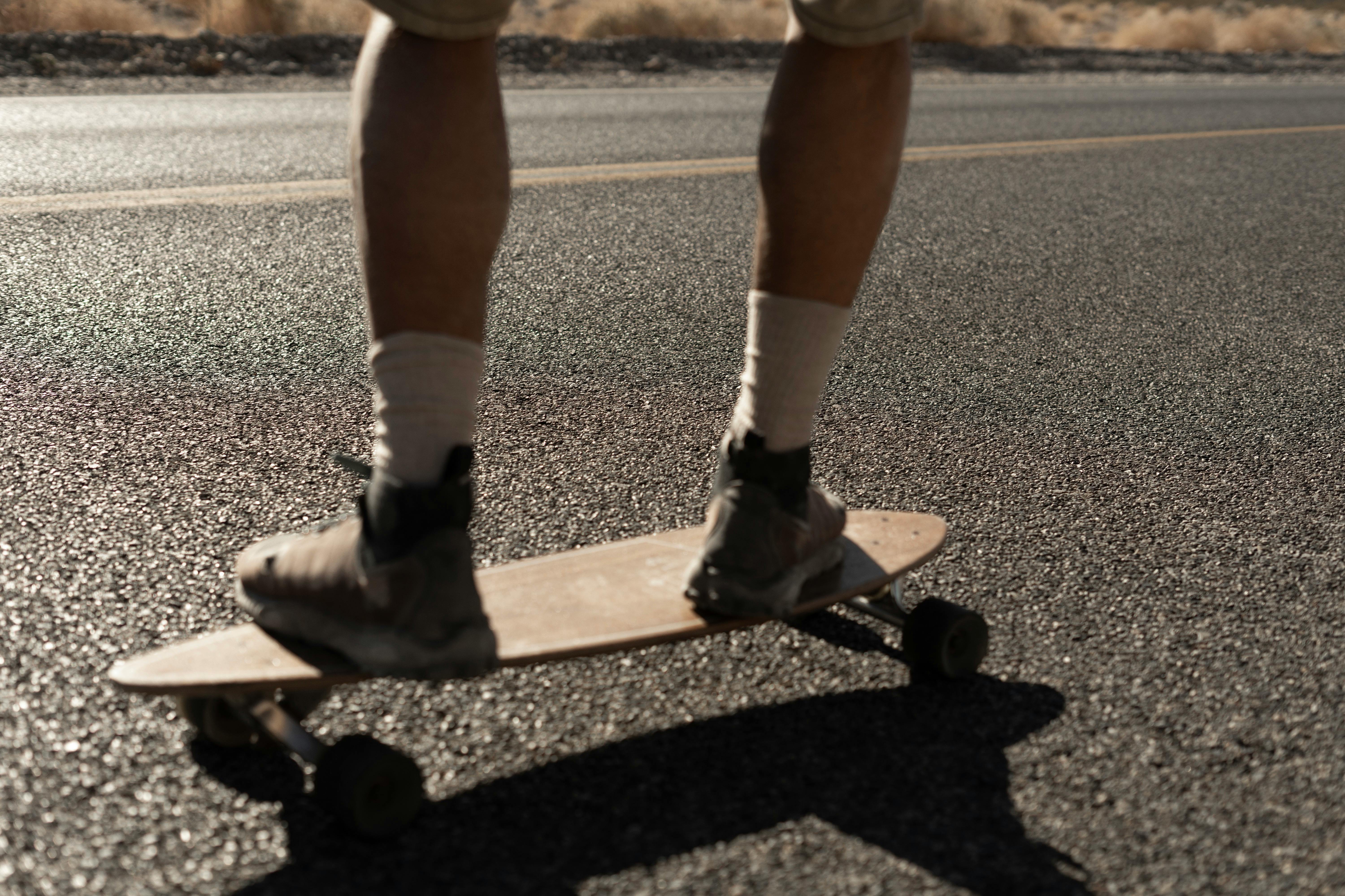 Person Longboarding on Asphalt Road · Free Stock Photo