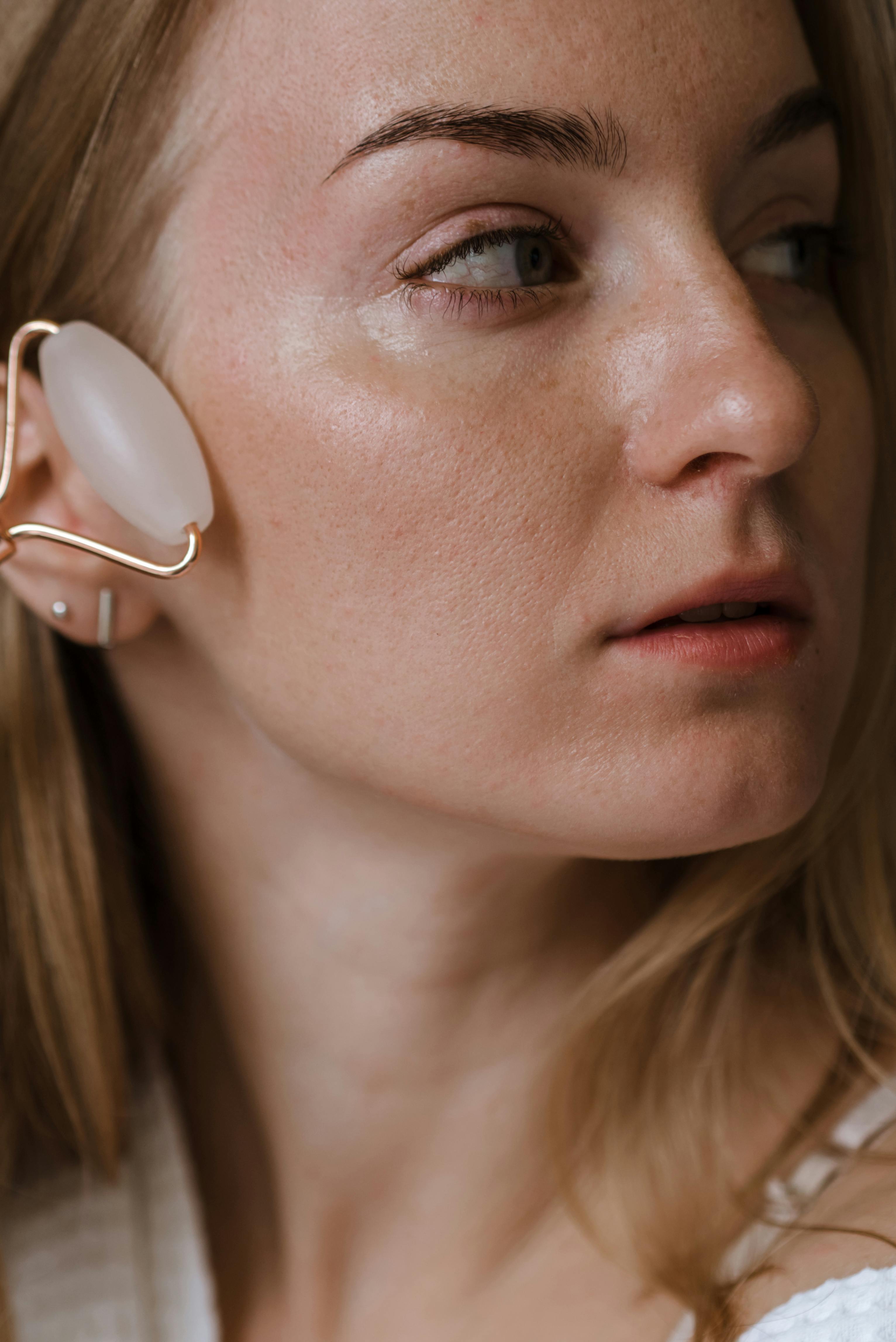 Close-Up Shot of a Woman Using a Face Roller · Free Stock Photo