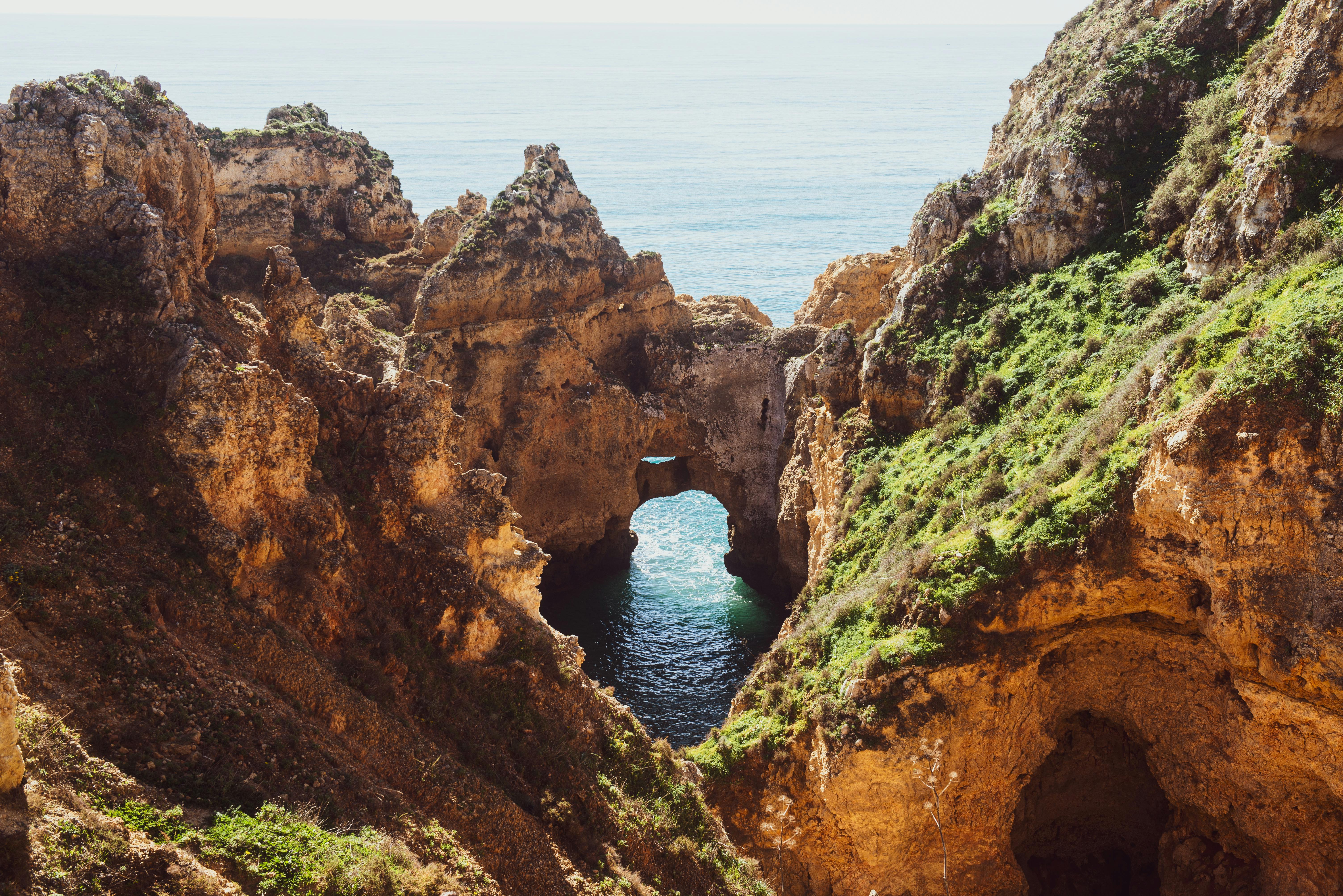 Rock Cliff Near Ocean With Kayakers and Speed Boat Passing · Free Stock ...