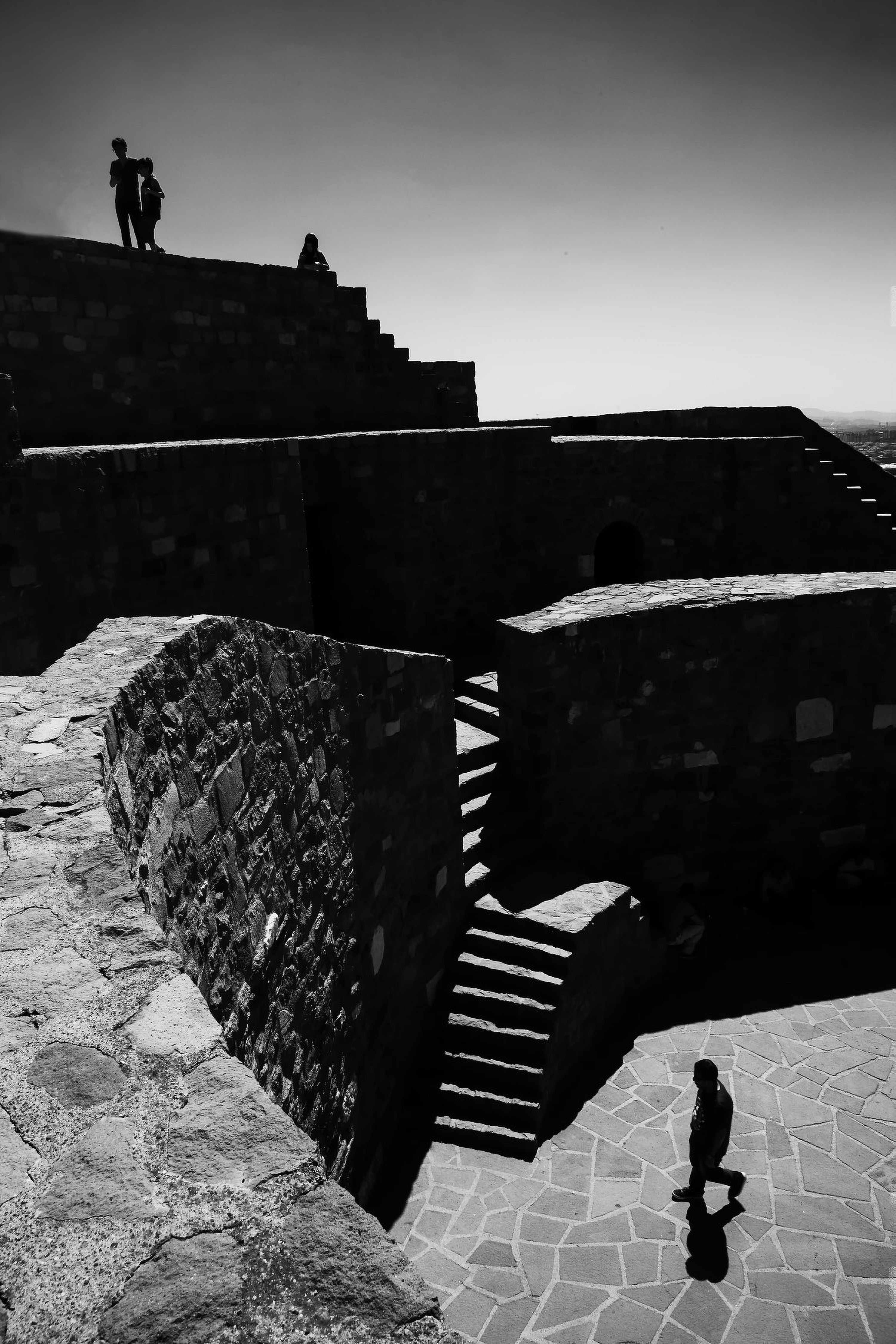 Man Walking Near Stone Walls with Stairs · Free Stock Photo