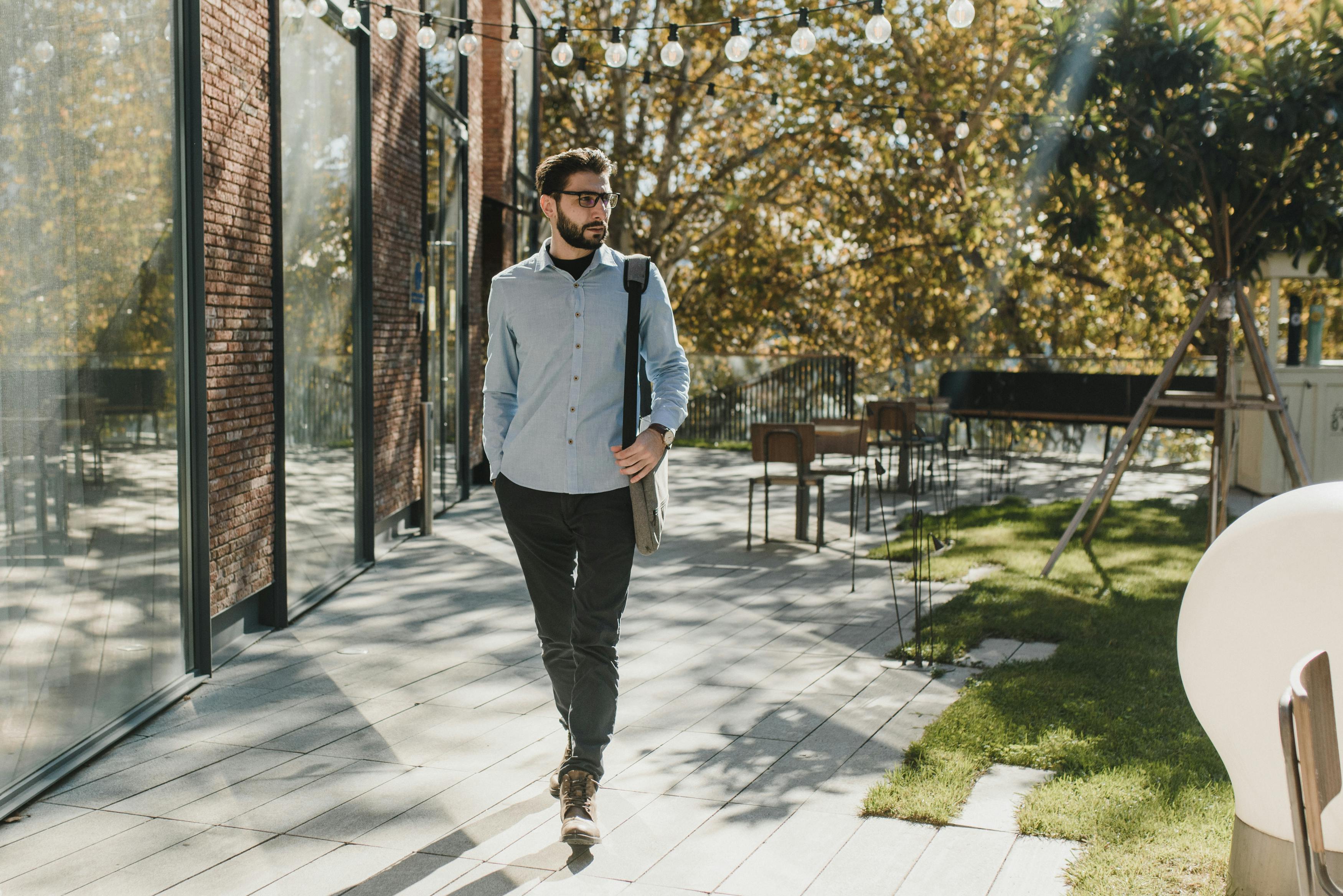 Man Walking on a Walkway Beside a Brick Building · Free Stock Photo