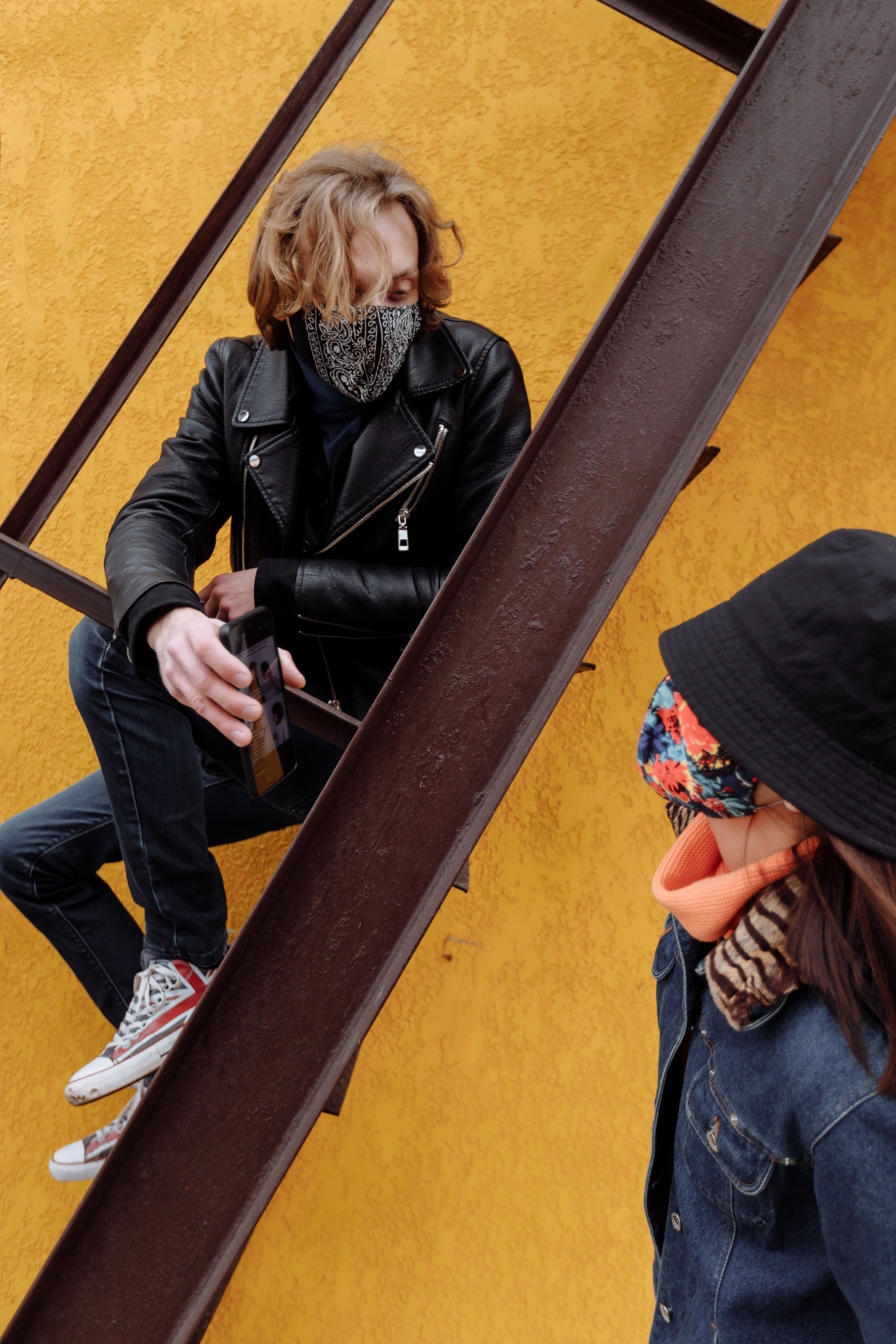 Man in Black Leather Jacket Sitting on a Metal Ladder · Free Stock Photo