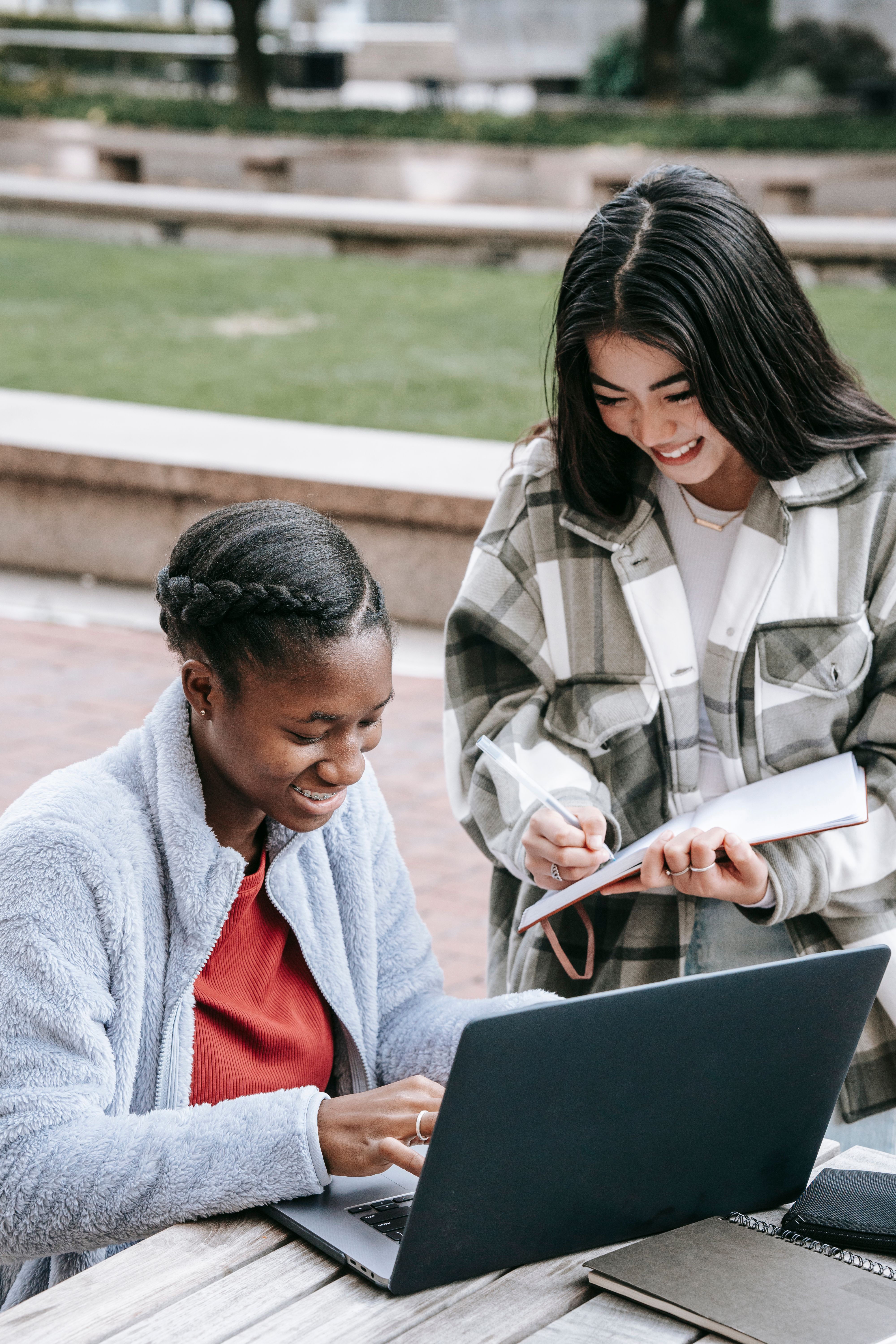 Content multiethnic students typing on laptop in town · Free Stock Photo