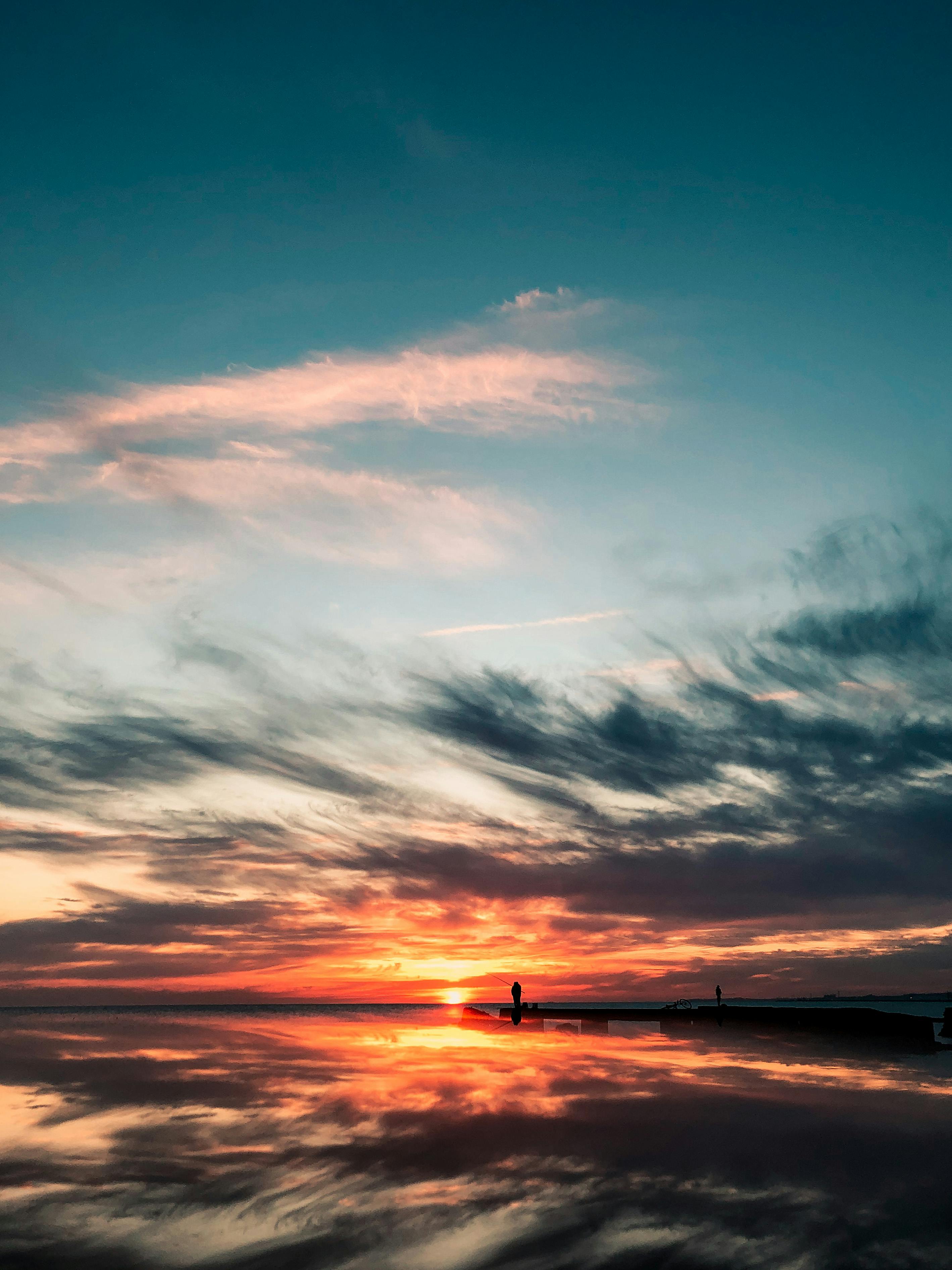 A Person Standing on a Cliff Overlooking the Sea during Golden Hour ...