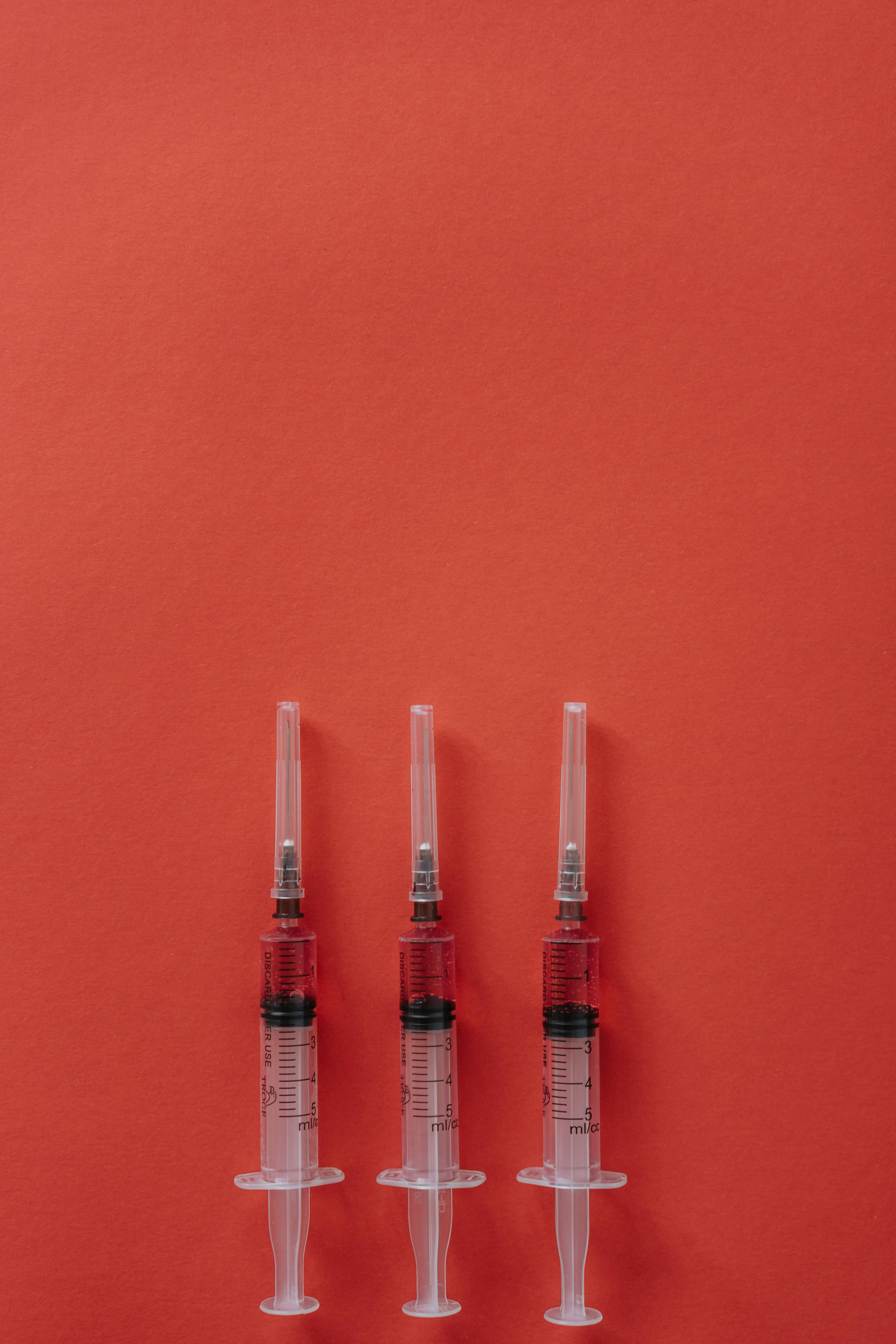 Close-Up Shot of Syringes on a Red Surface · Free Stock Photo