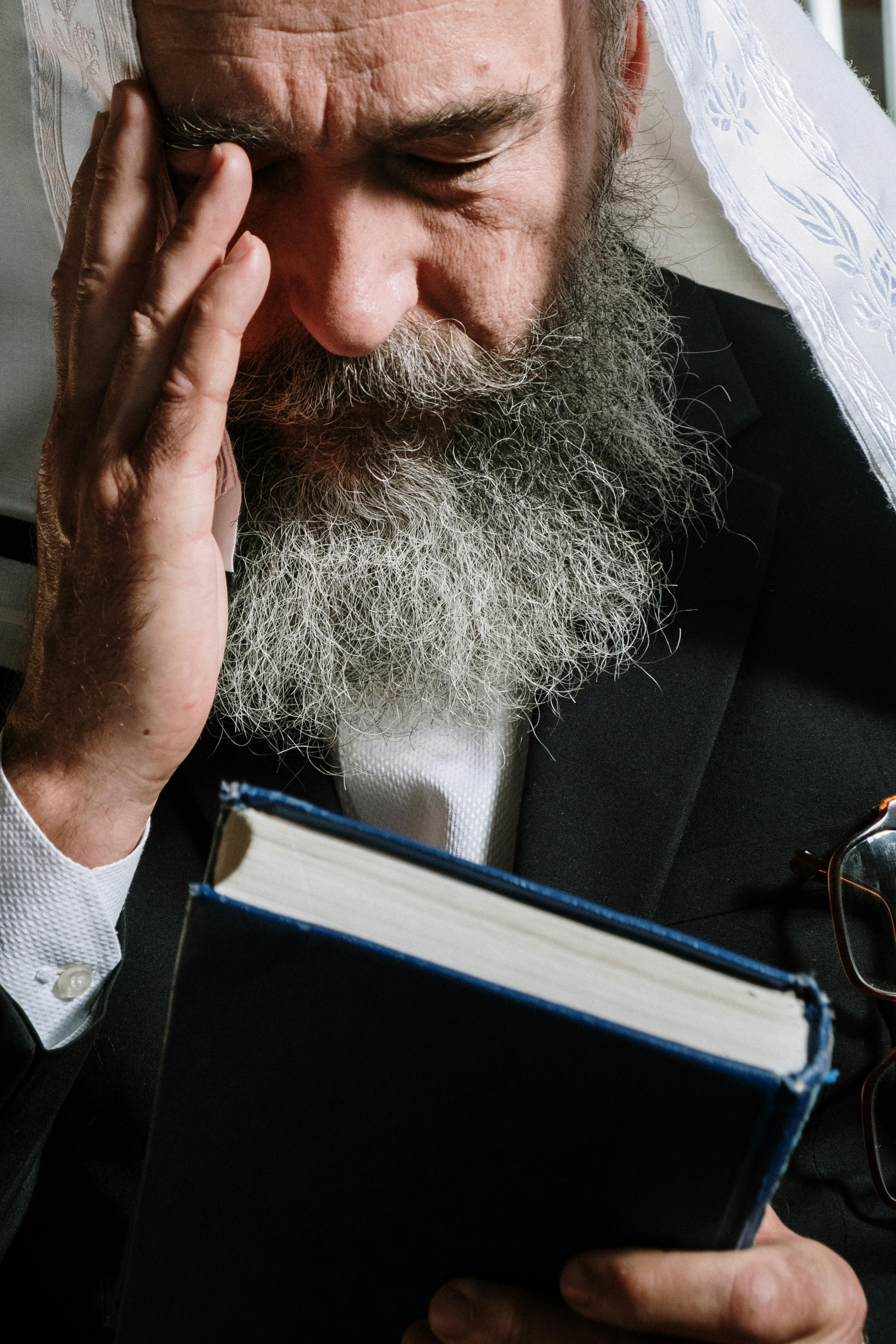 Man in Black Suit Holding Blue Book while Praying · Free Stock Photo