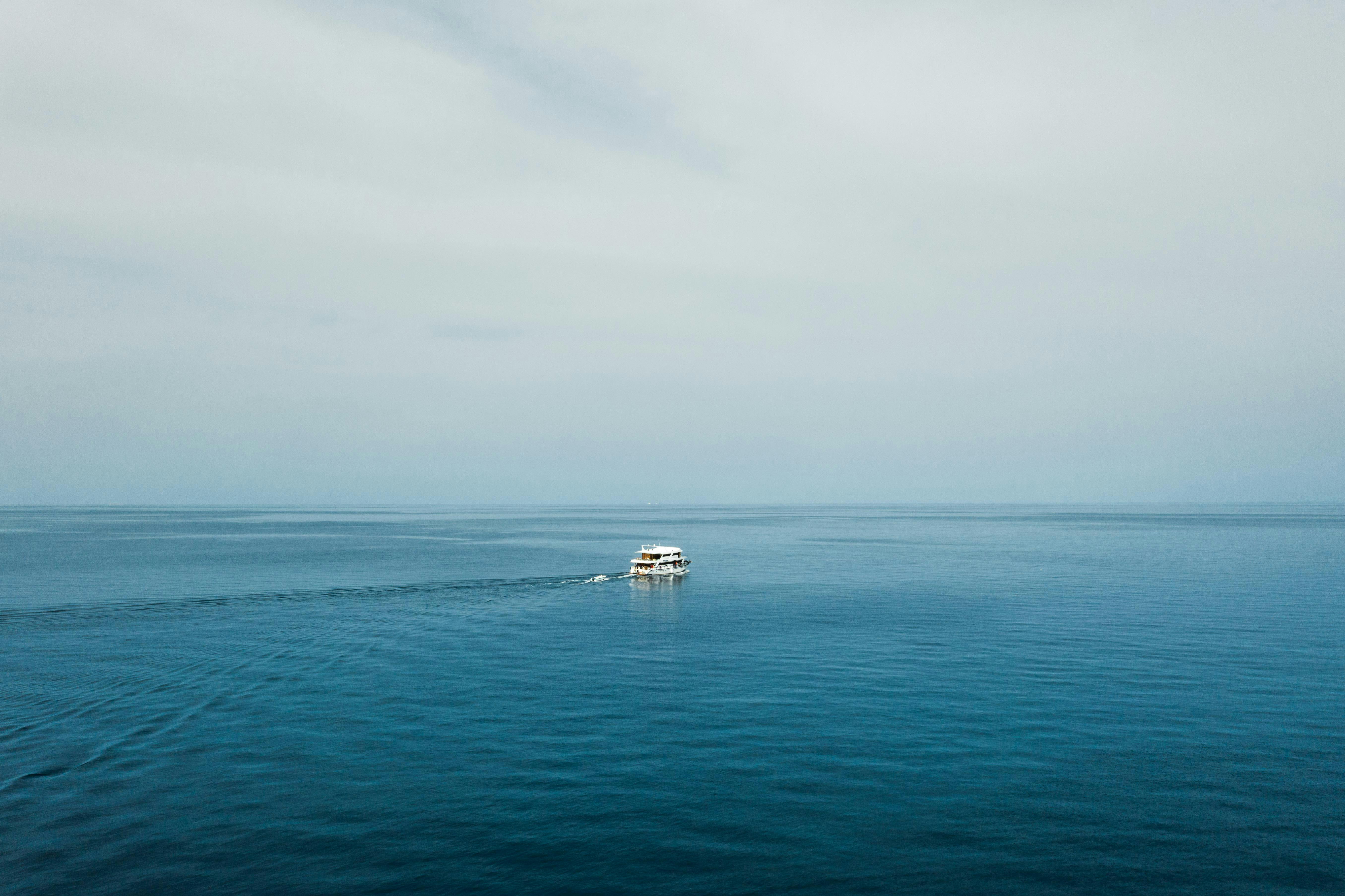 Sailboat floating in sea near rocky cliff · Free Stock Photo