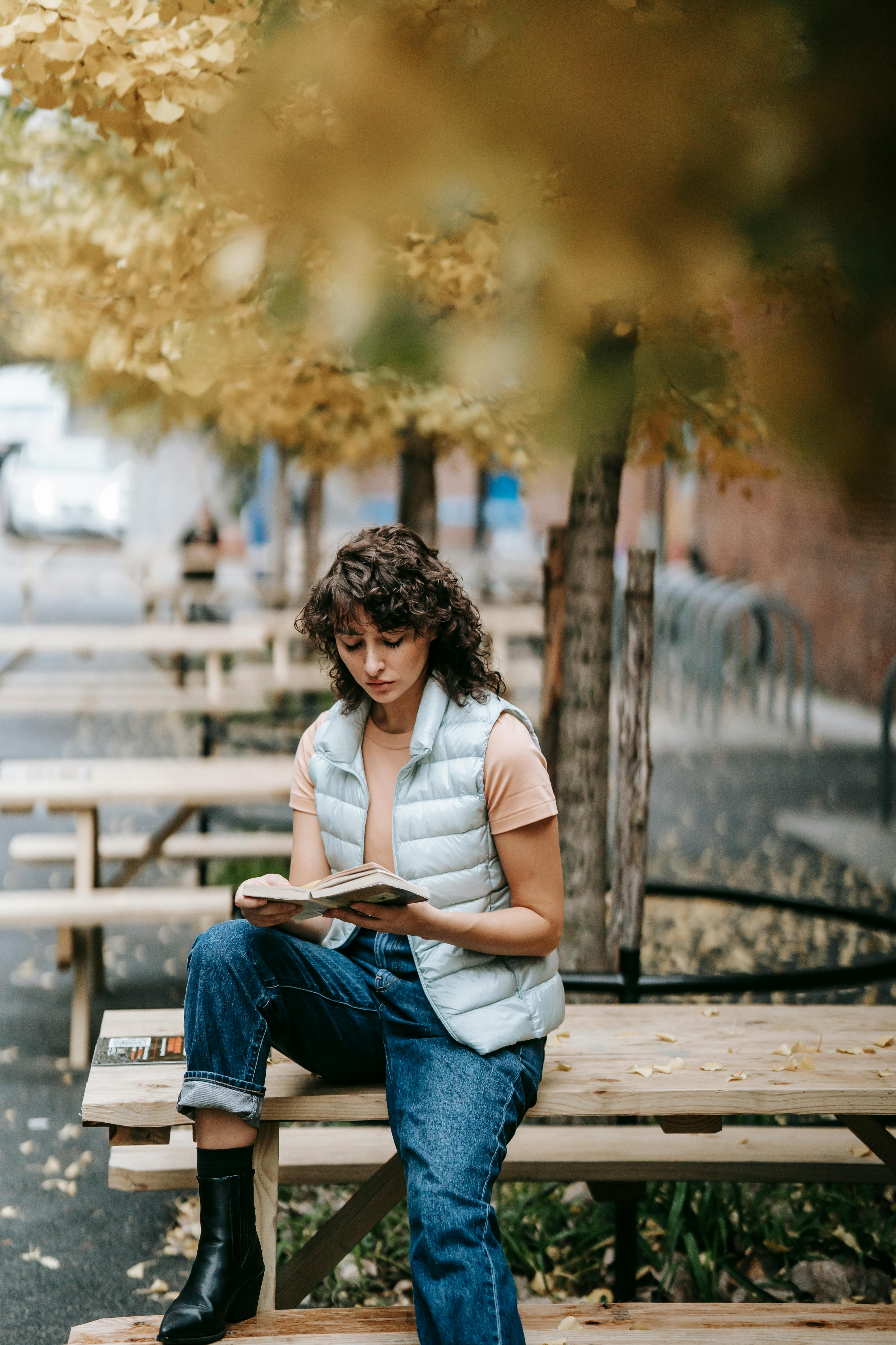 Stylish female reading book on street in autumn time in daylight · Free ...