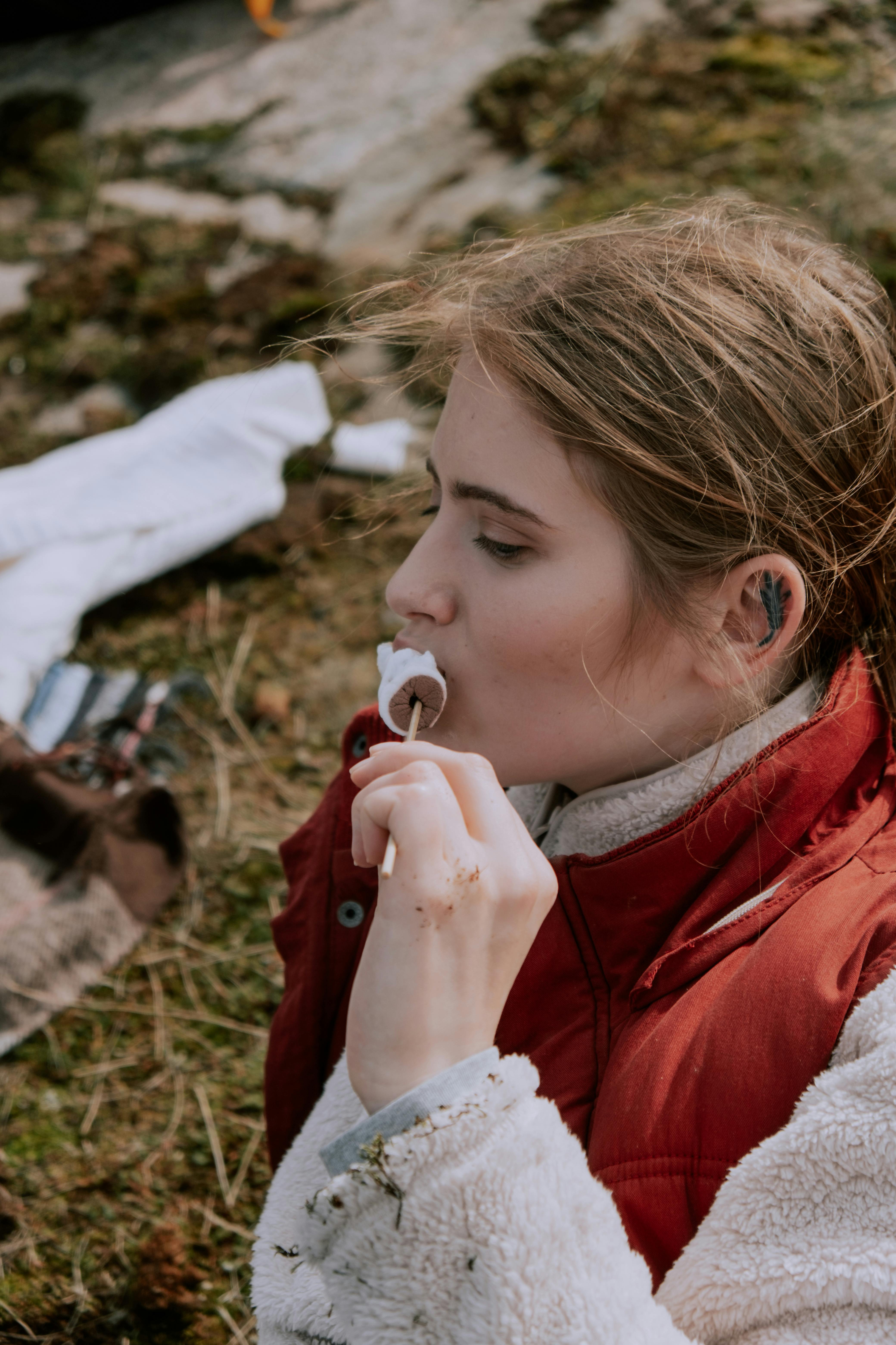 Young Woman Eating a Marshmallow on a Stick · Free Stock Photo