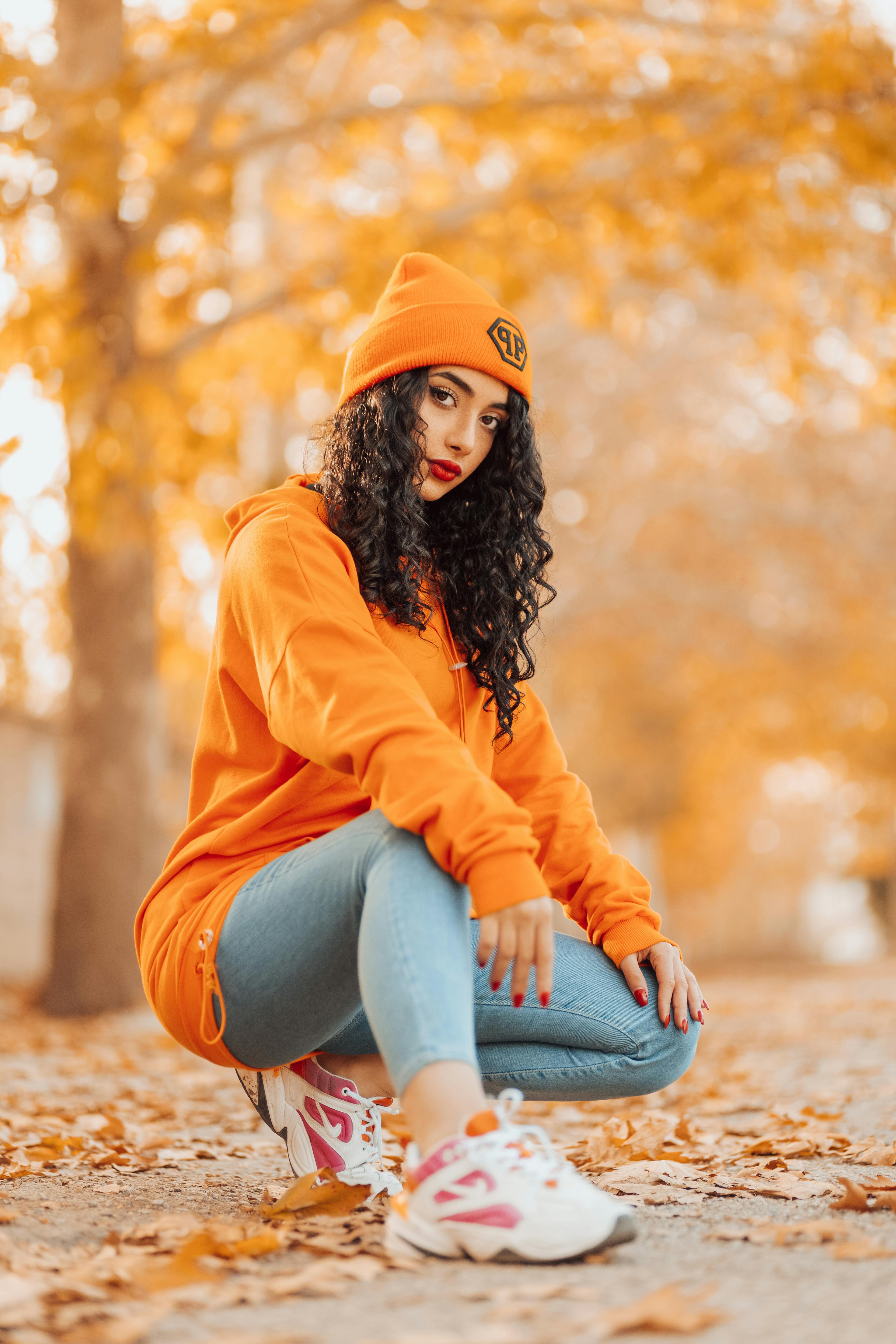 Portrait of Curly Haired Woman in Jeans Crouching · Free Stock Photo