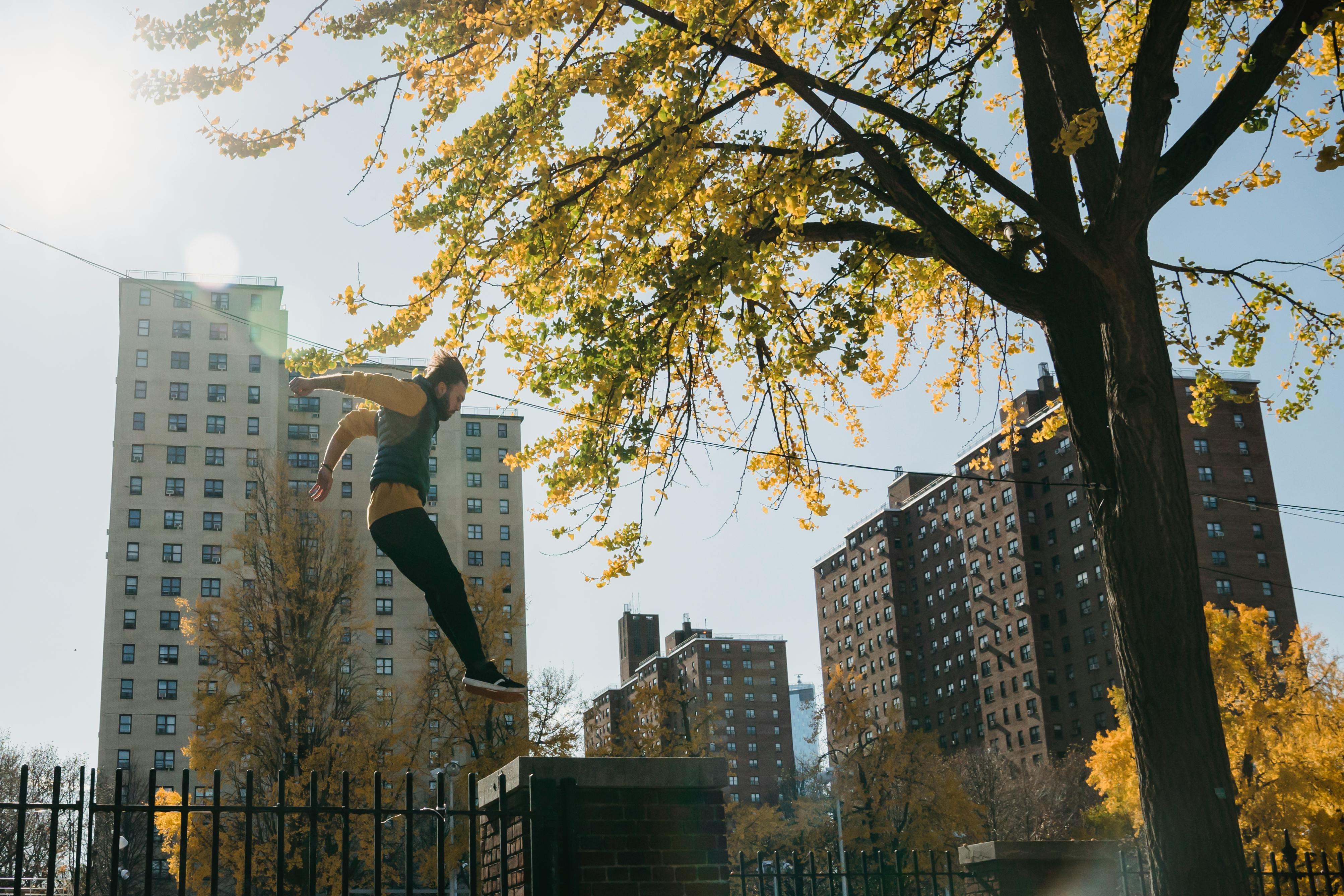 Flexible man jumping on border of fence · Free Stock Photo