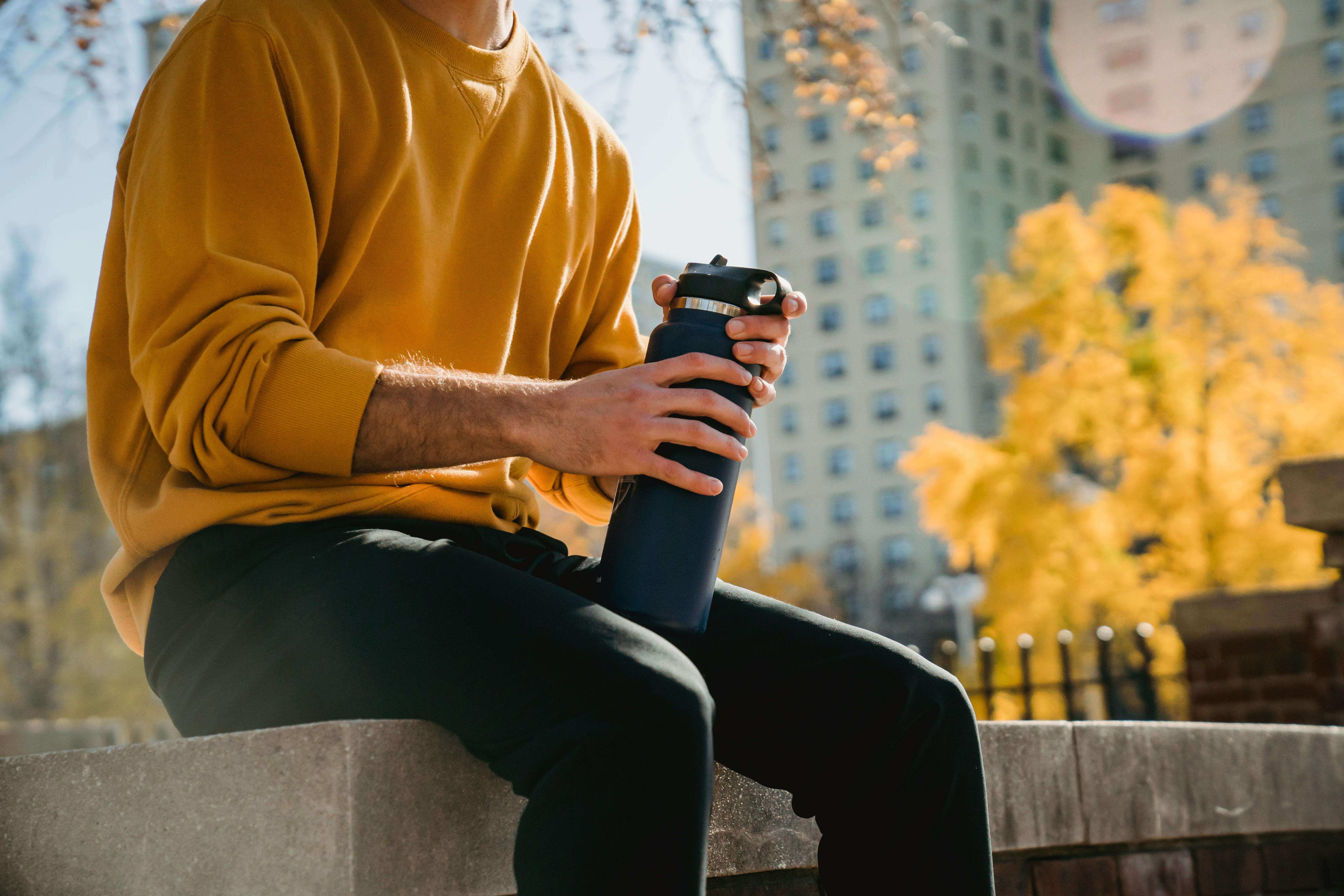 Faceless guy sitting on brick fence outdoors · Free Stock Photo