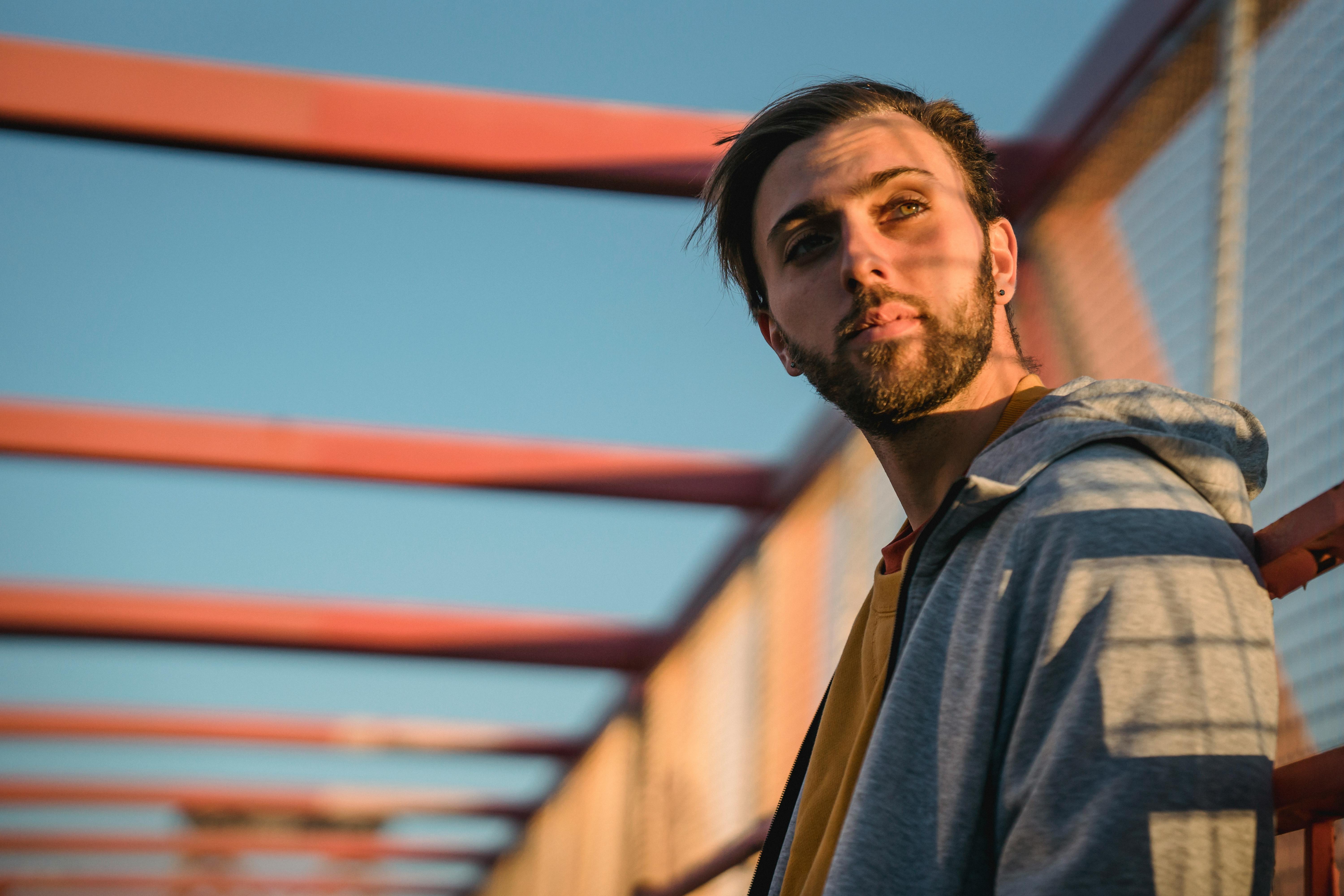 Contemplative millennial man on urban bridge in soft sunlight · Free ...