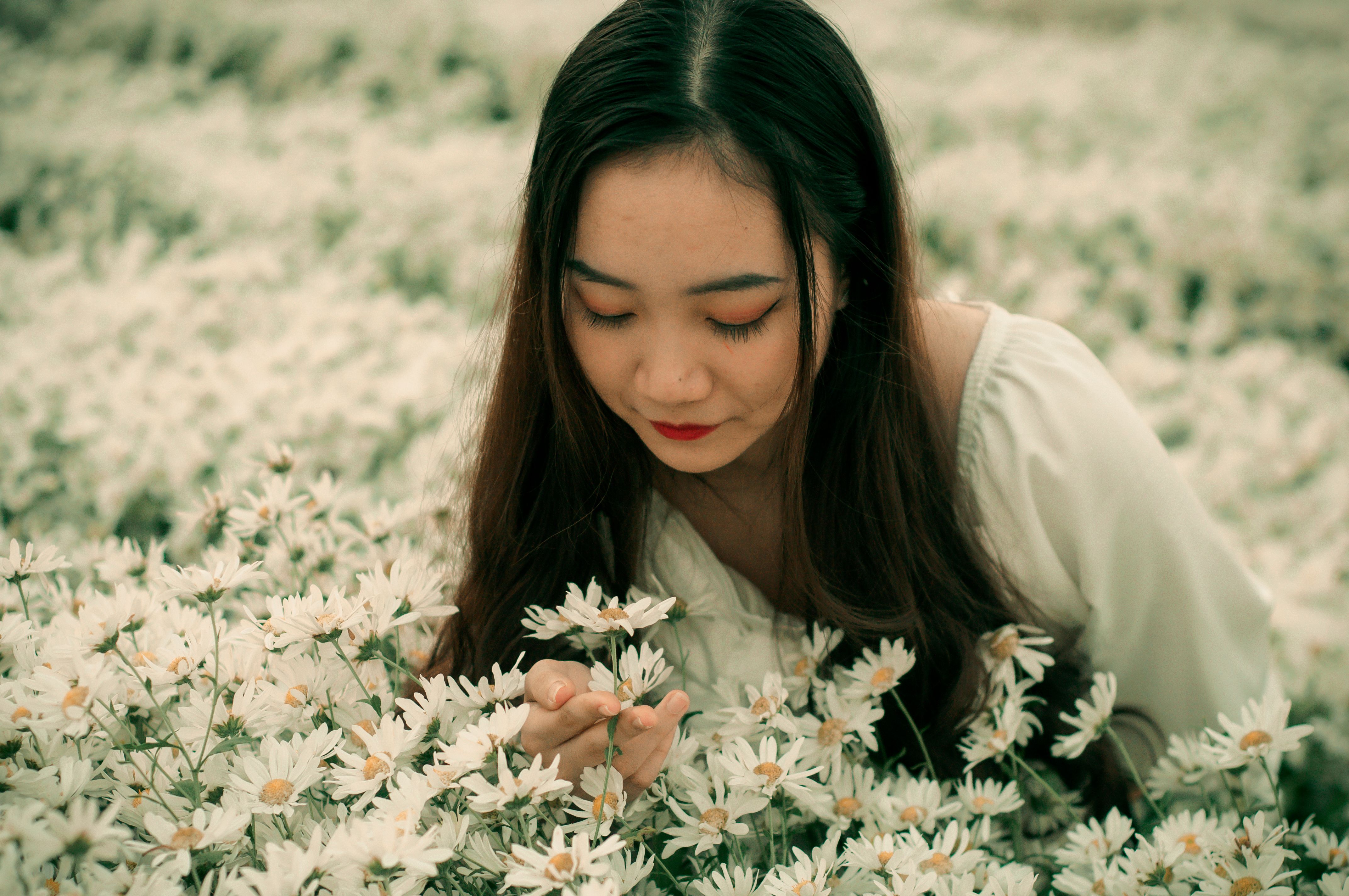 Close-Up Shot of a Pretty Woman Smelling White Daisies · Free Stock Photo