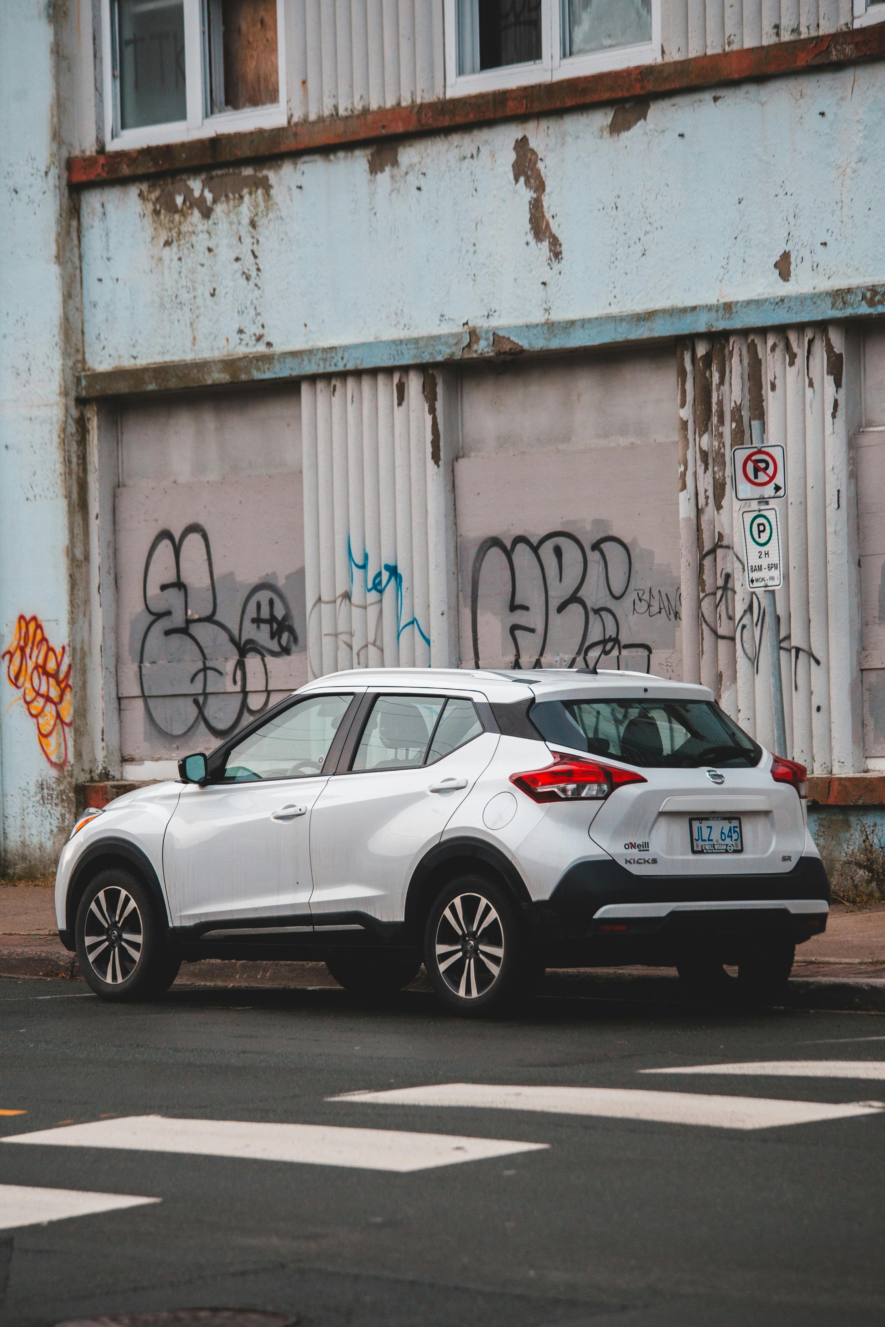 Expensive white car placed near wall of building on street in daytime ...