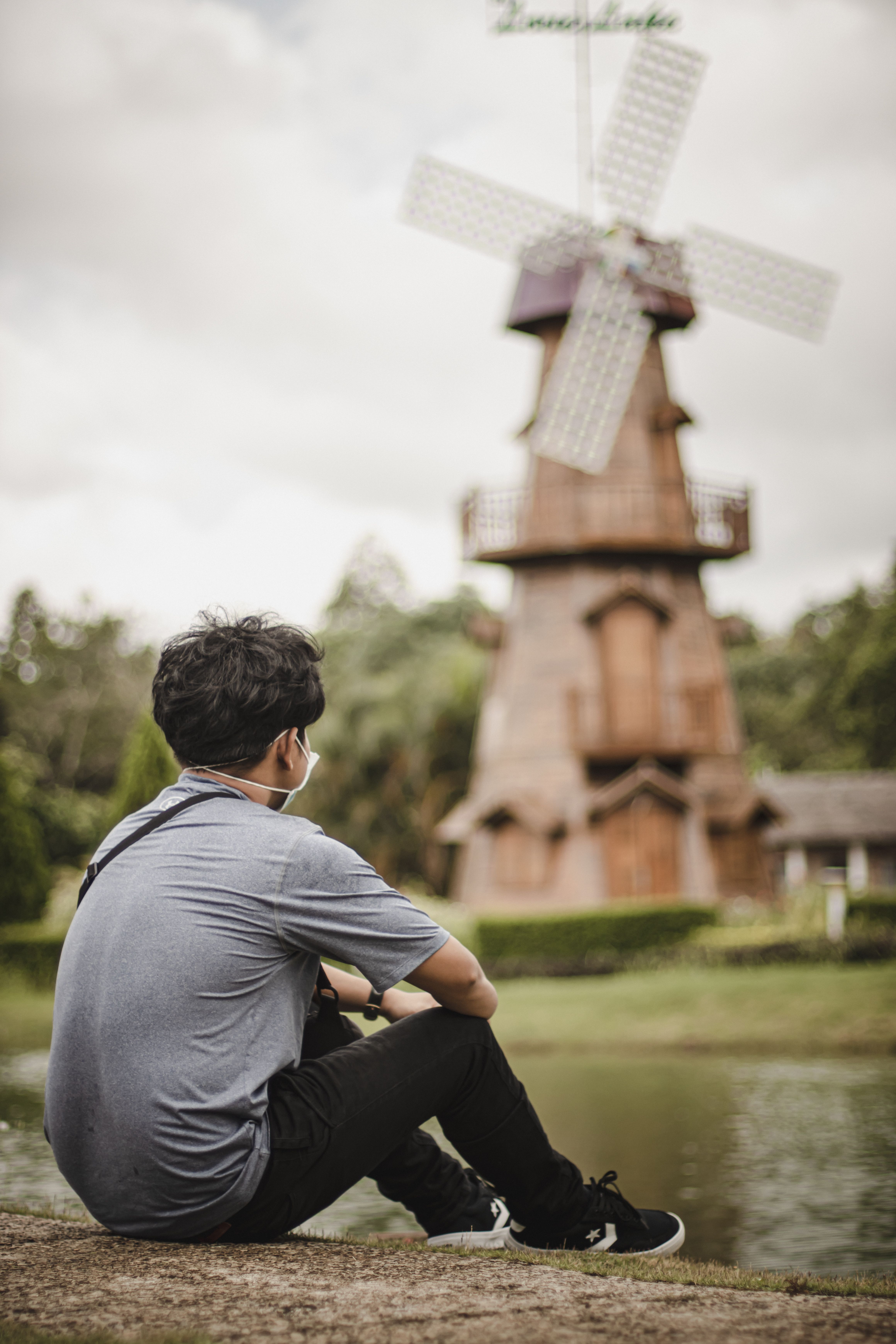 Man Sitting on Ground Looking at Windmill · Free Stock Photo