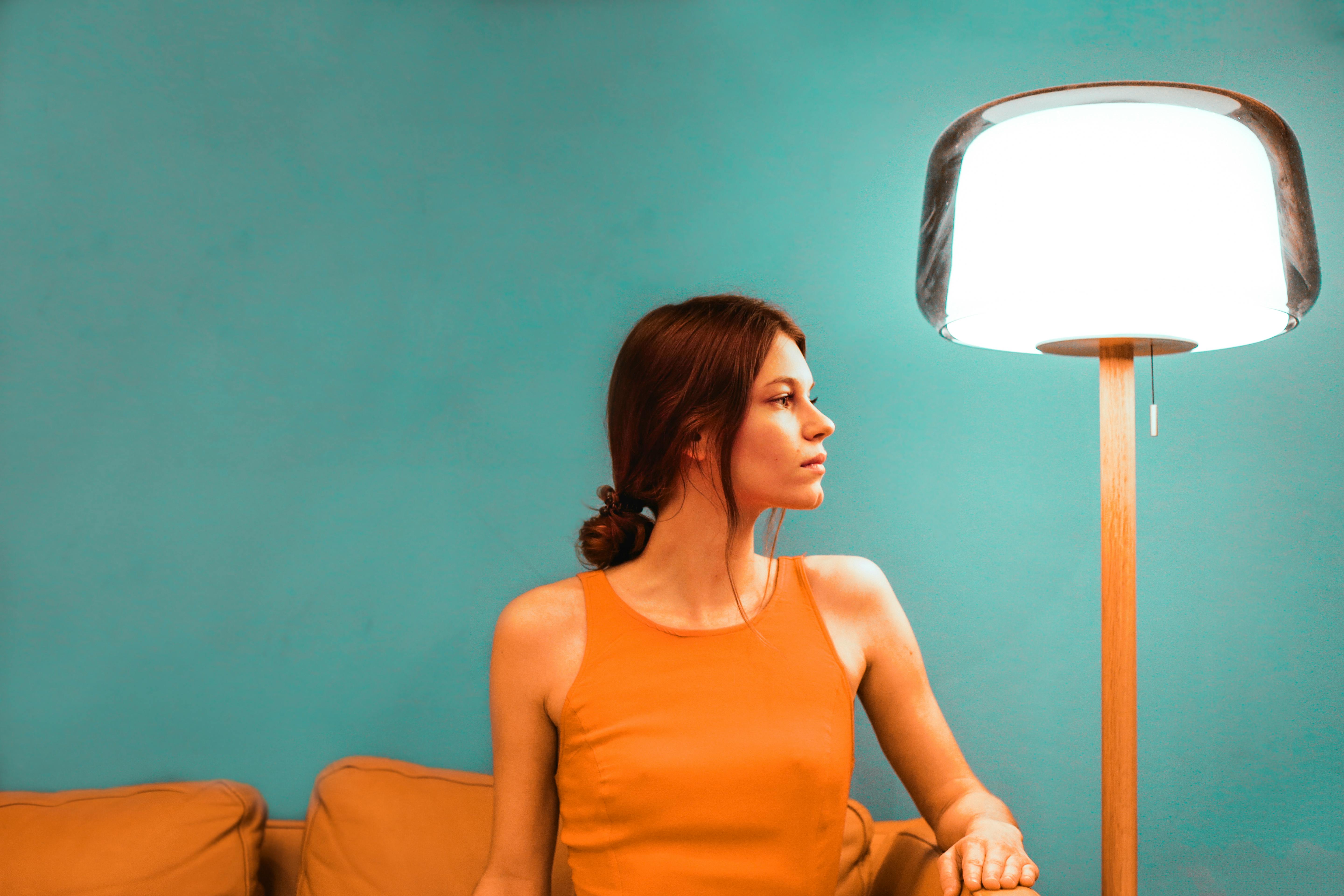 Thoughtful woman sitting near lamp · Free Stock Photo