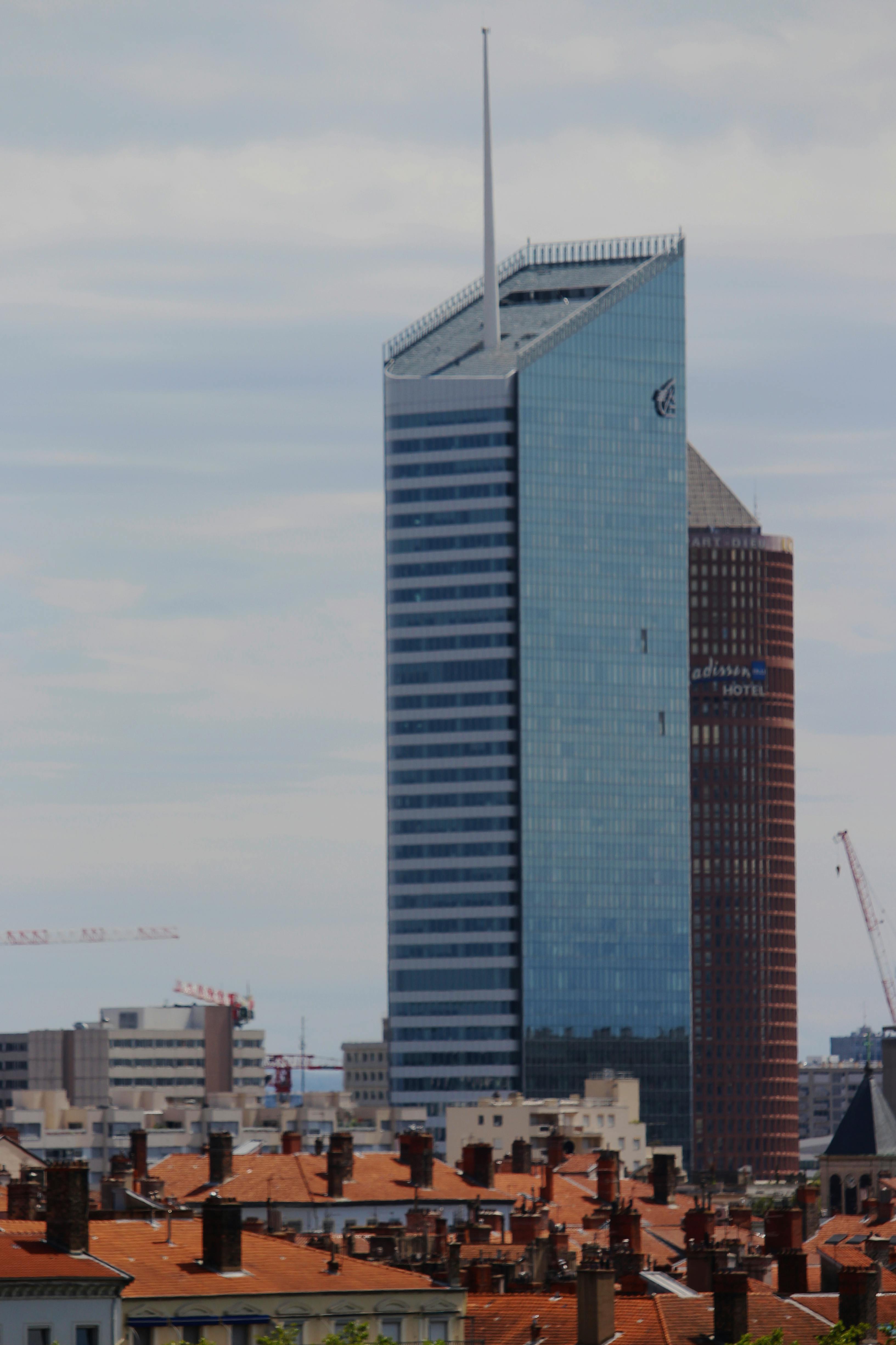 A Blue Rise Glass Building with Slanted Roof Top · Free Stock Photo