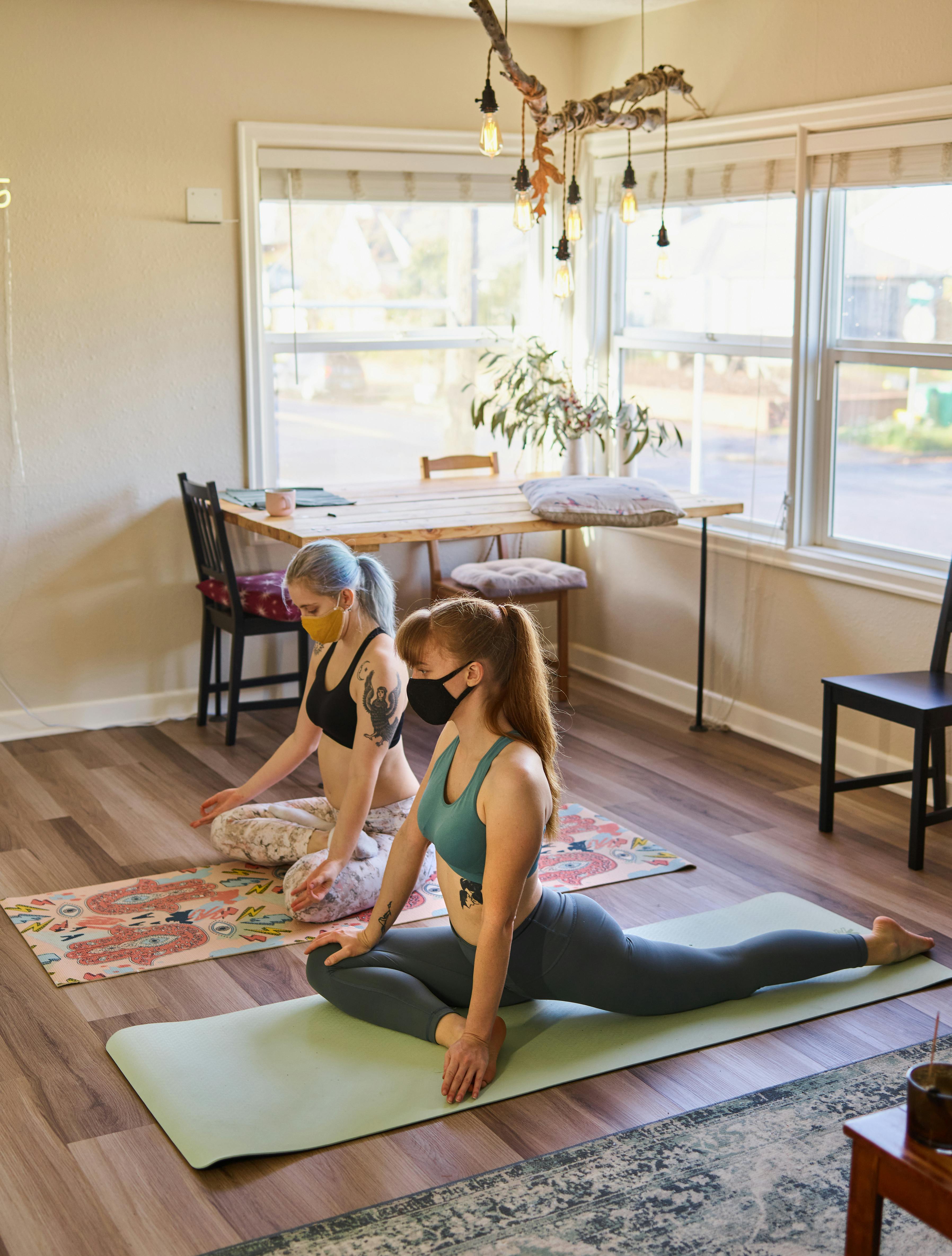 Women Sitting on Rug Stretching Sideways · Free Stock Photo