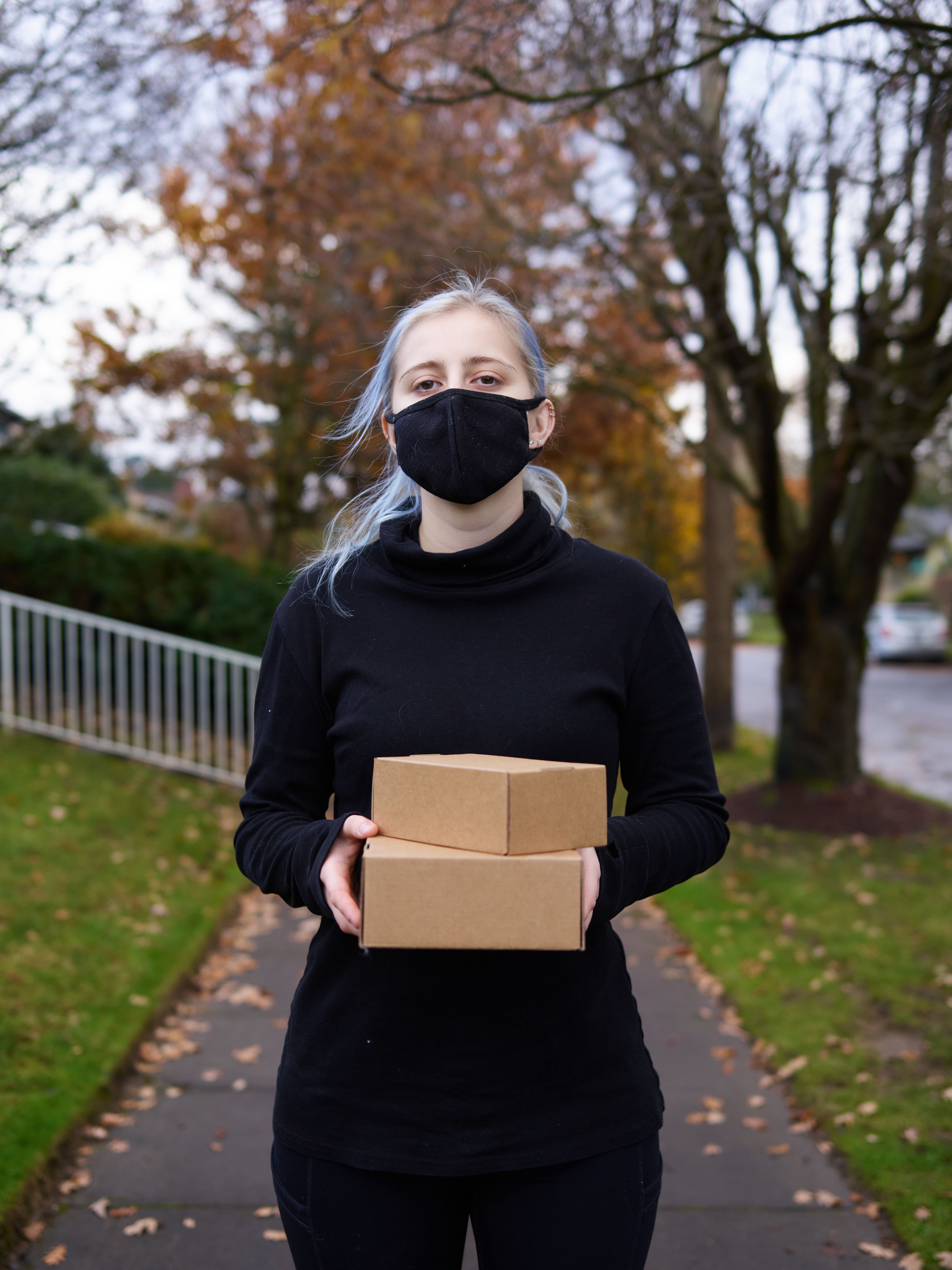 A Person Handing Out Cardboard Boxes to a Person Wearing a Face Mask ...