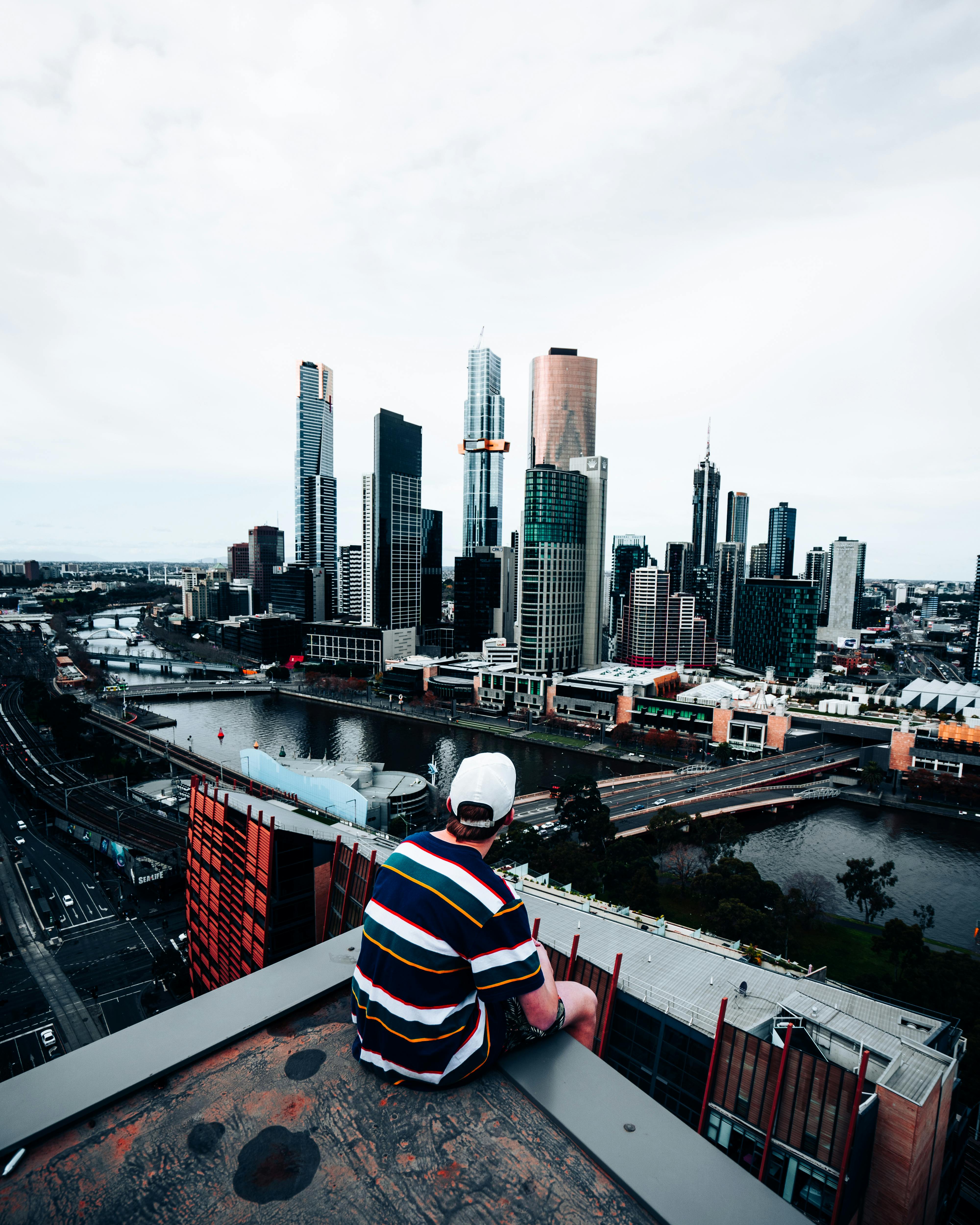 Man in White Red and Black Striped Shirt Sitting on the Edge of a ...