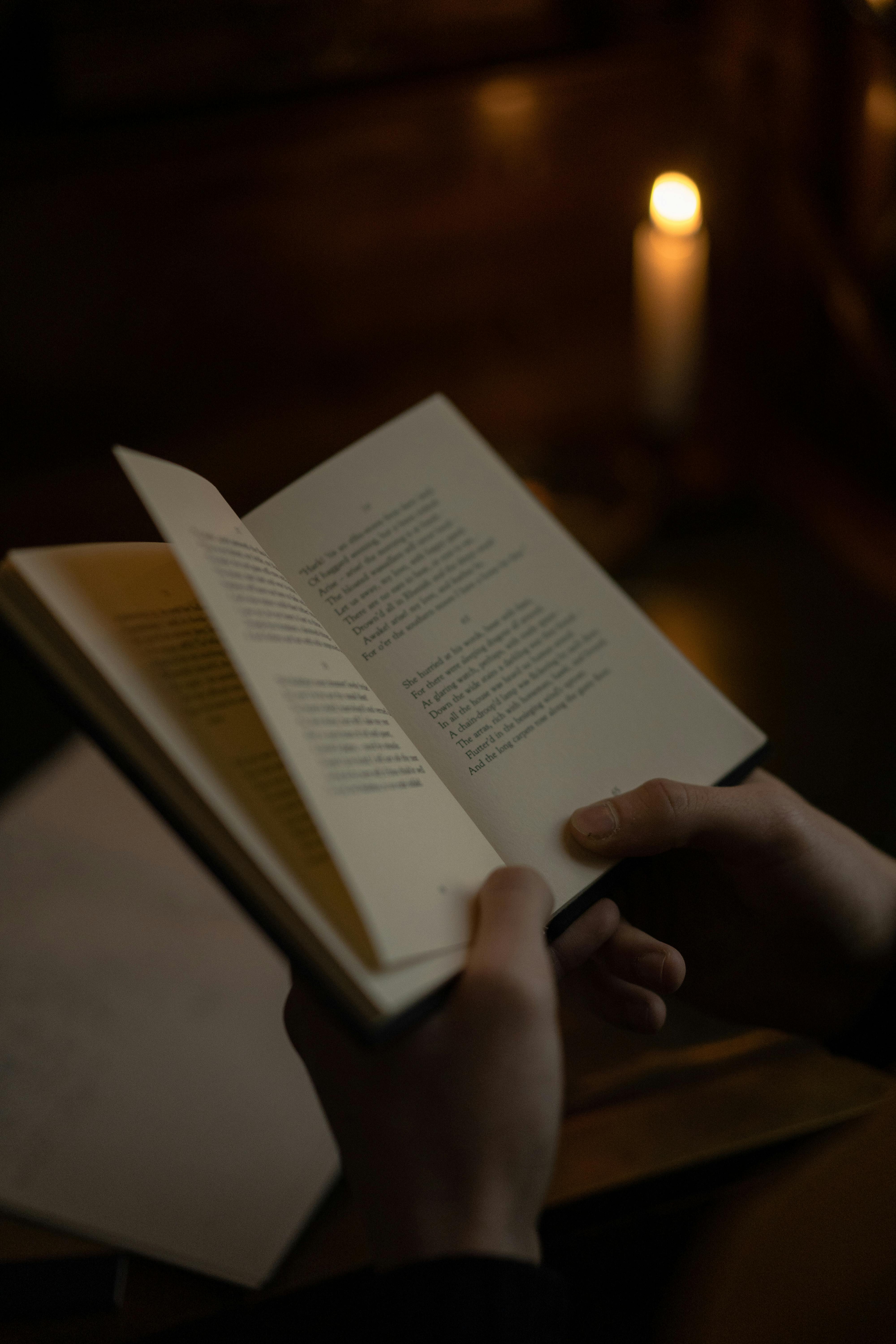 Person Reading a Book Near the Lighted Candle · Free Stock Photo