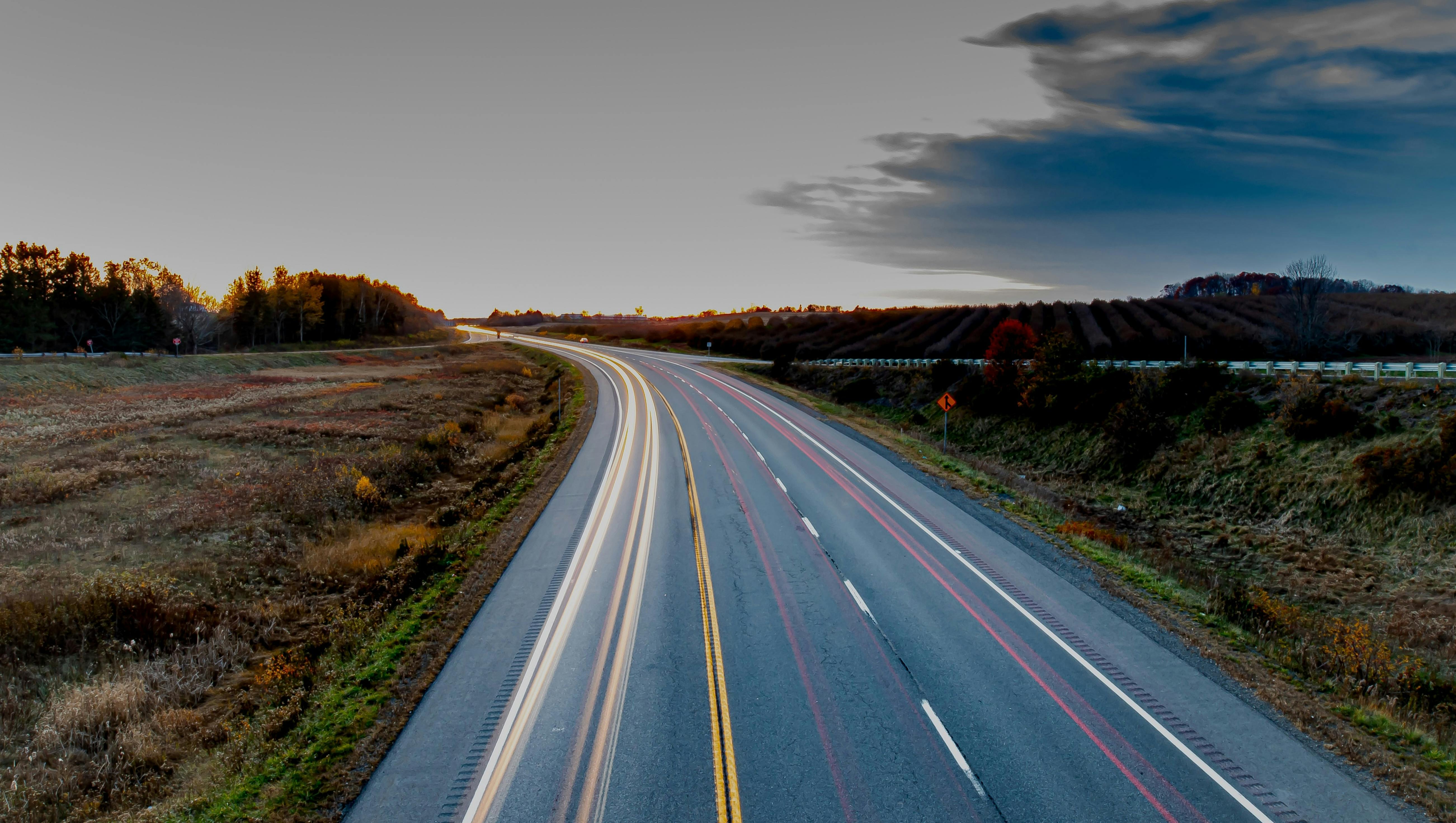 Gray Asphalt Road Between Green Grass Field Under Gray Cloudy Sky ...