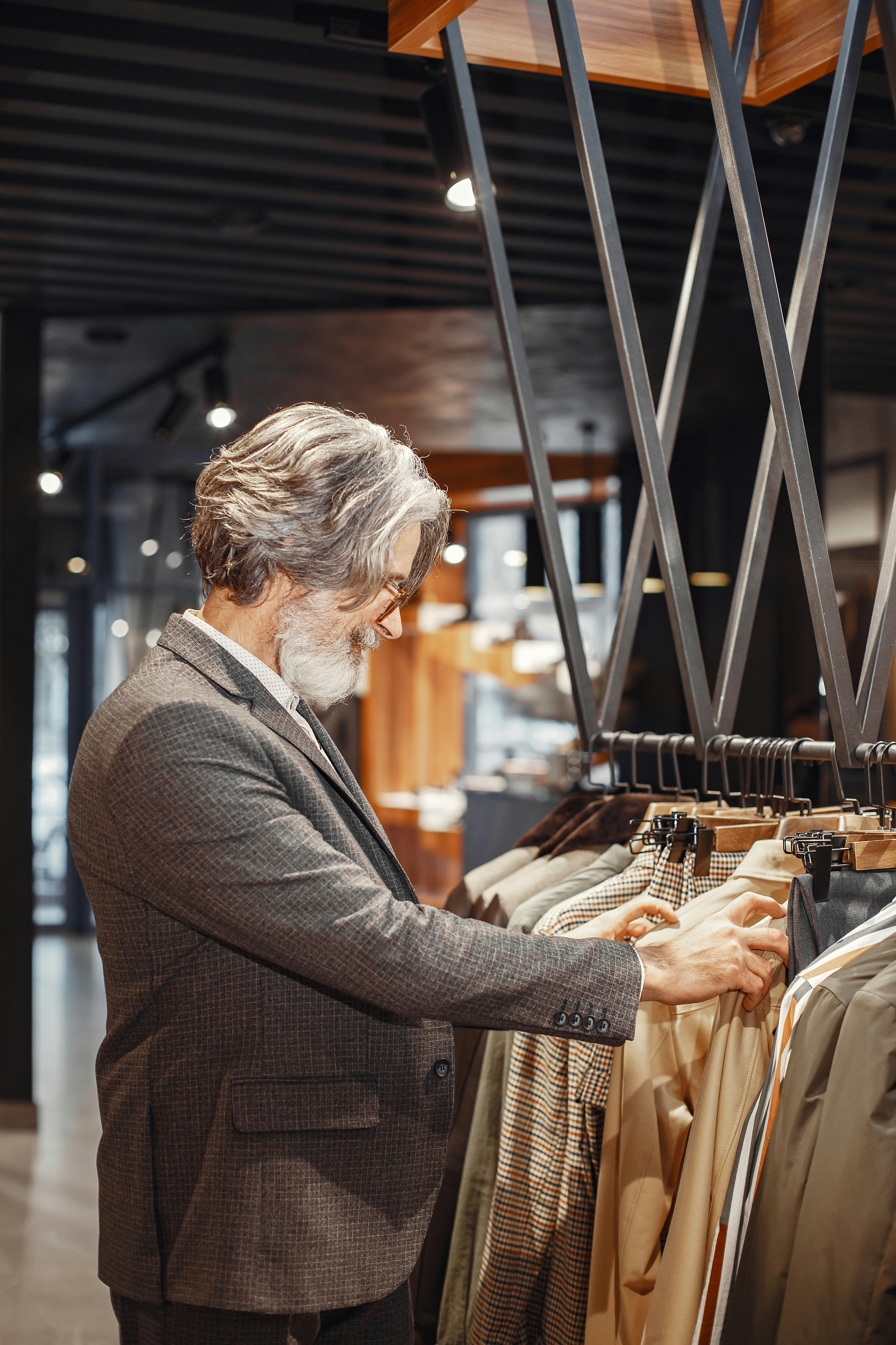 Man in Gray Suit Looking at the Hanging Clothes · Free Stock Photo