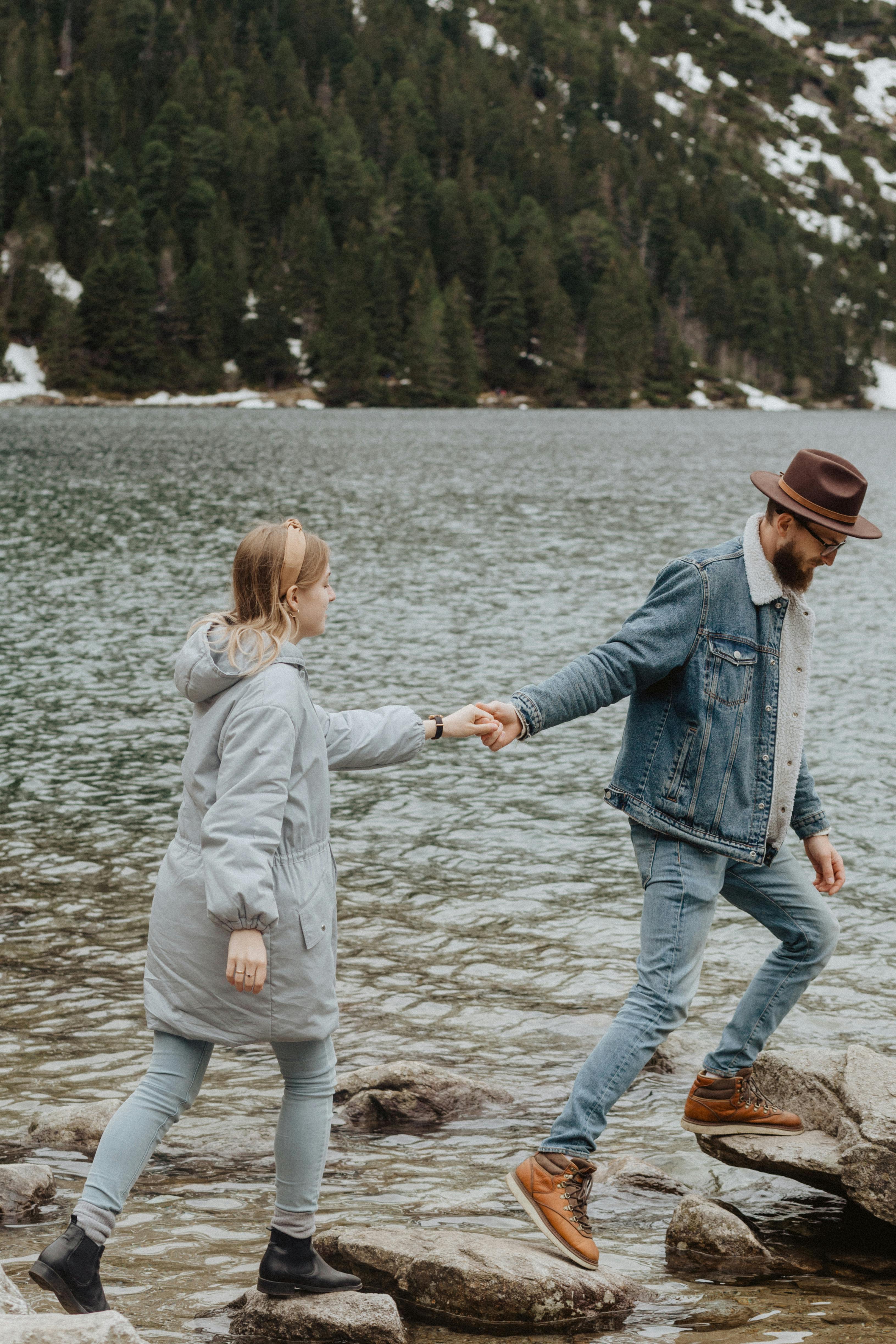 Man Helping A Woman Step On A Rock · Free Stock Photo