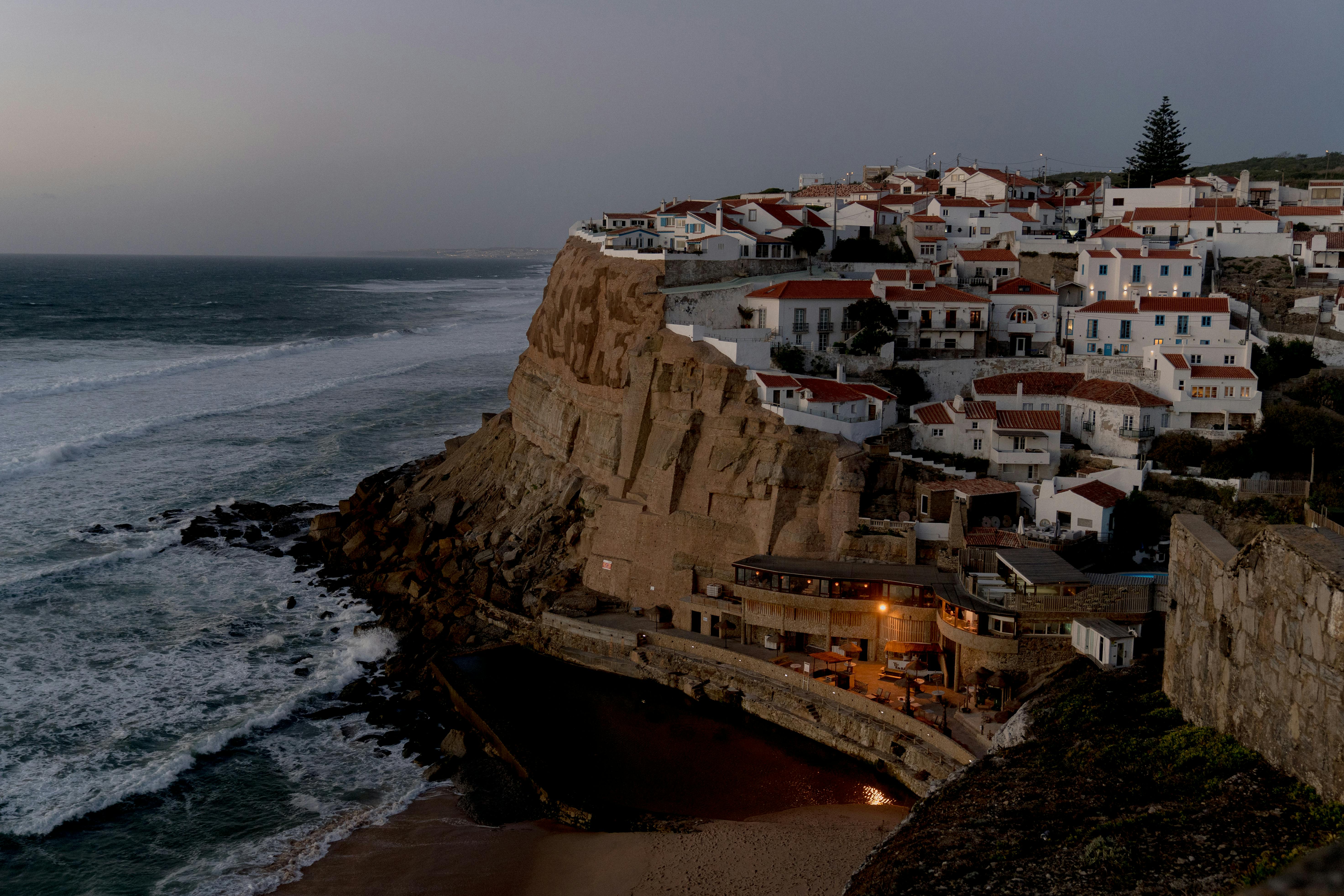 Houses Perched on a Cliff Overlooking a Sandy Beach and Rocky Coastline ...
