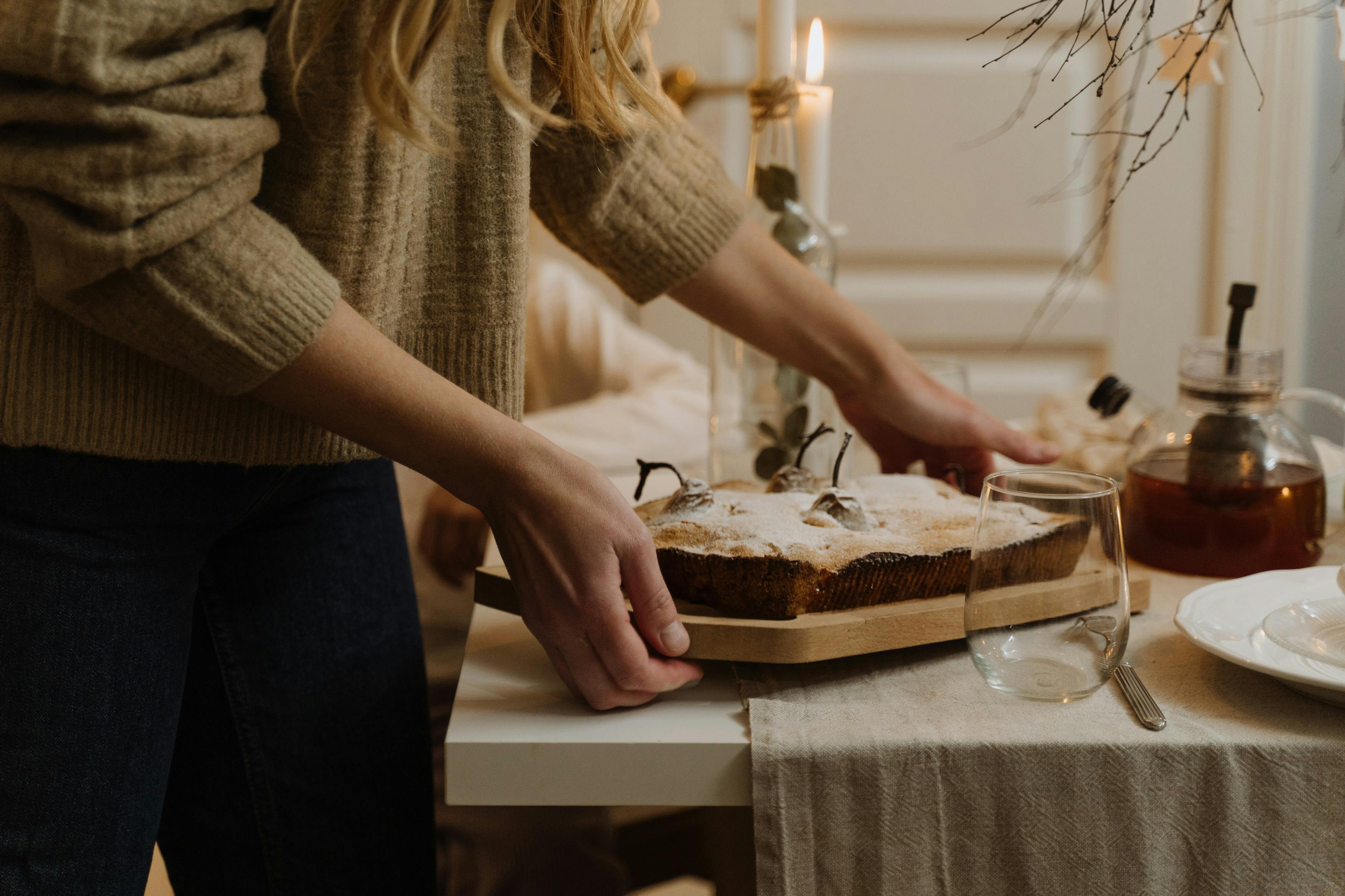 A Person Placing a Cake on a Dining Table · Free Stock Photo