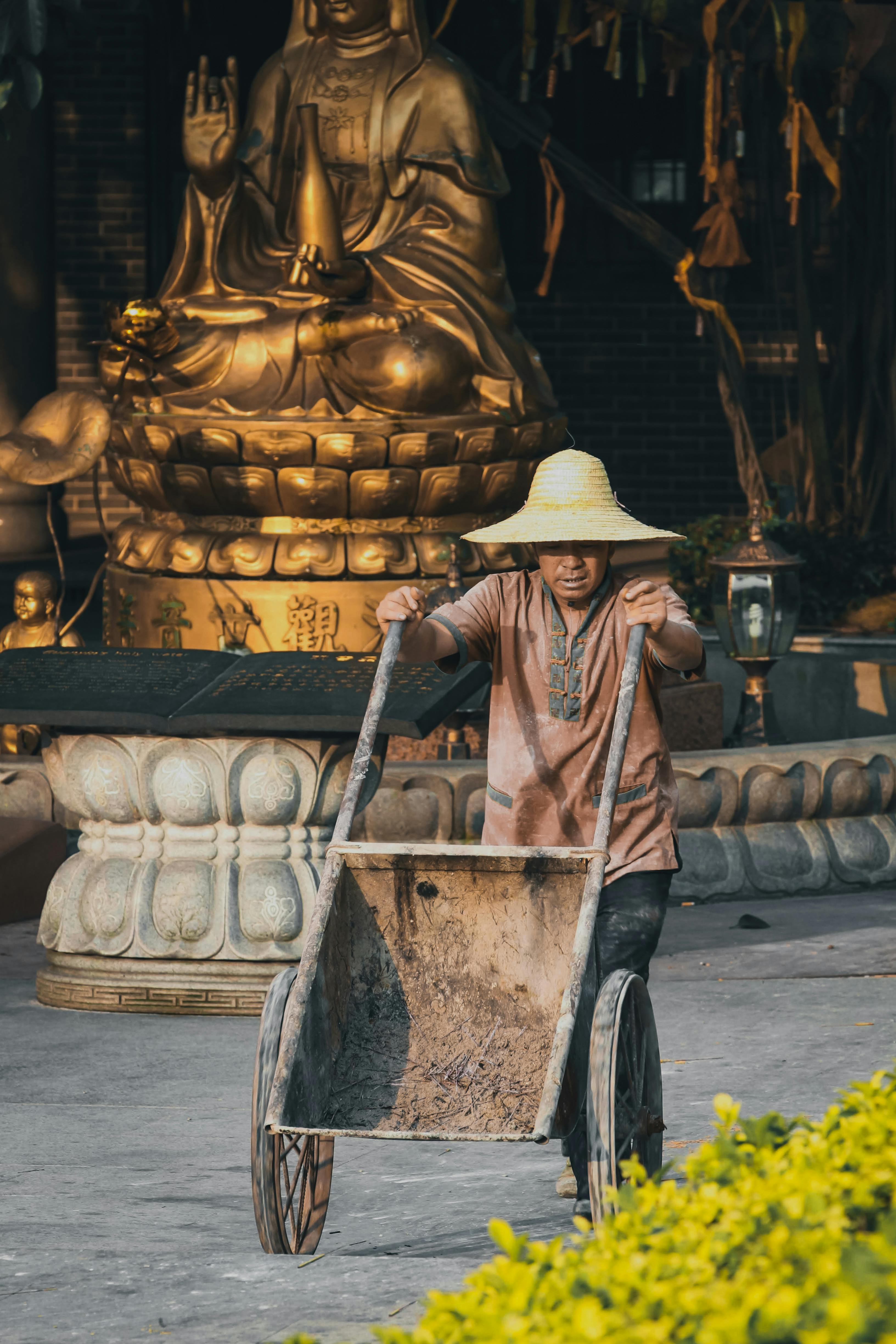 Ethnic man with wheelbarrow walking on city pavement · Free Stock Photo