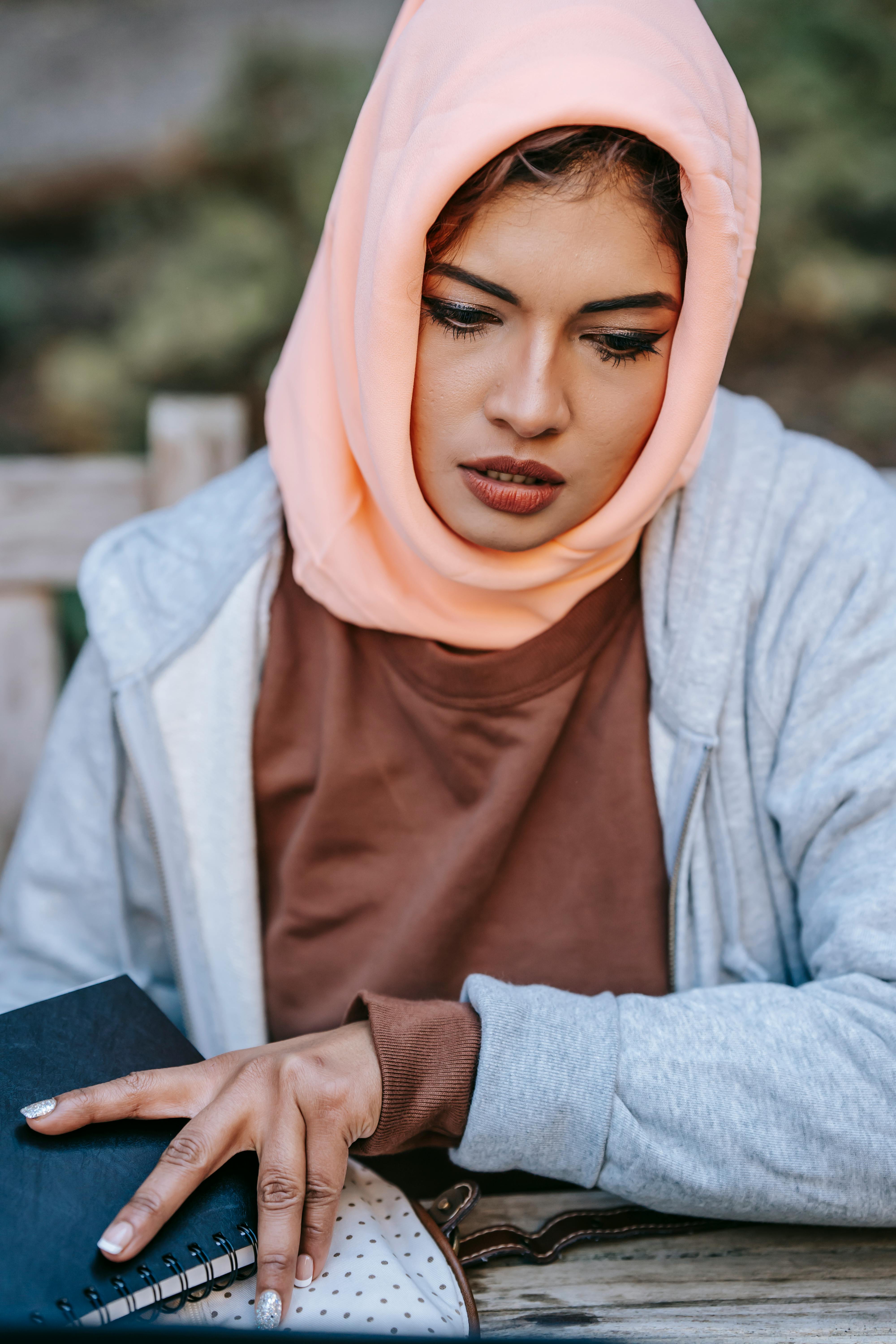 Serious young Muslim lady in traditional headscarf working with ...