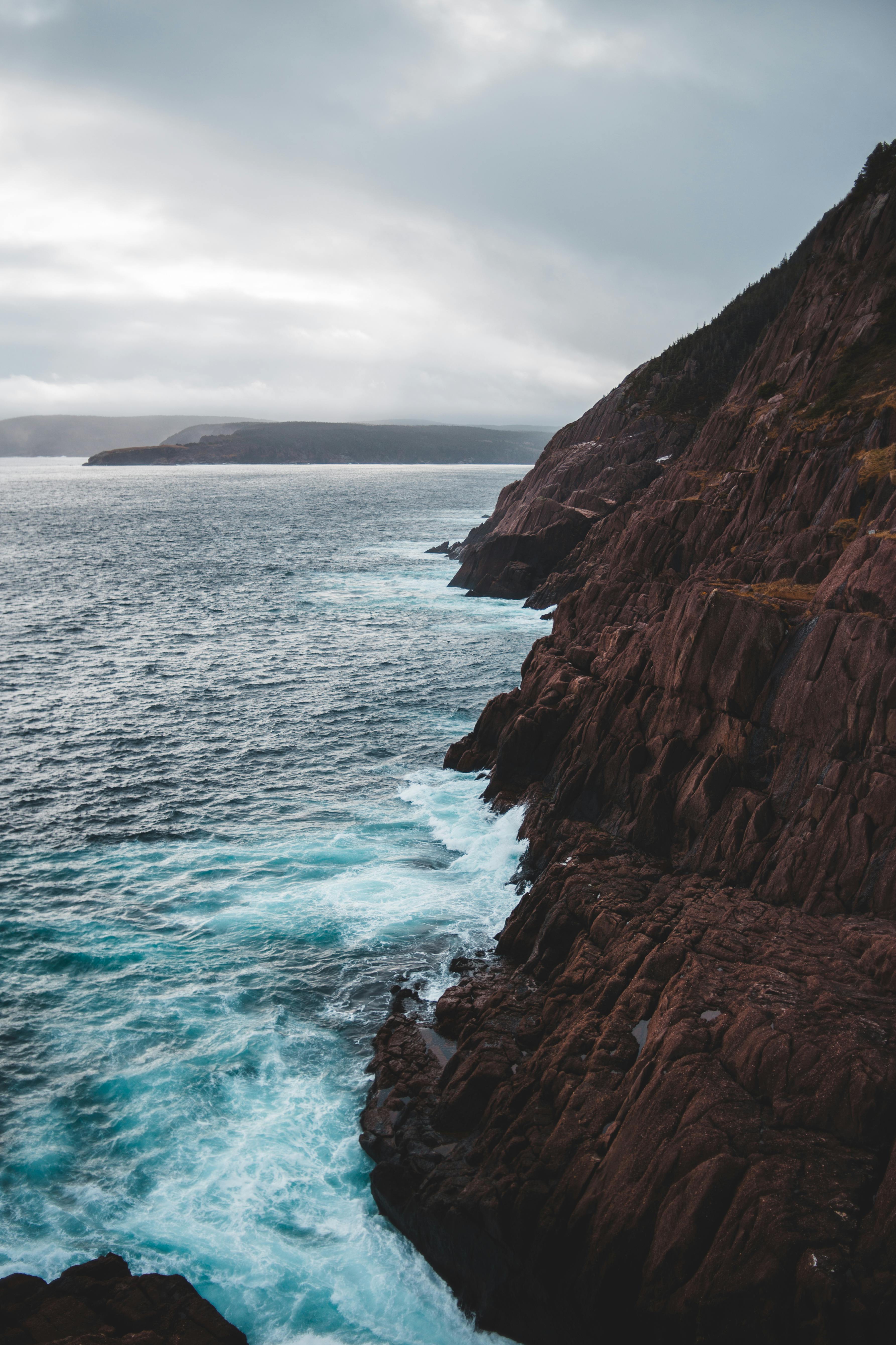 Dry ridges and foamy ocean under cloudy sky · Free Stock Photo