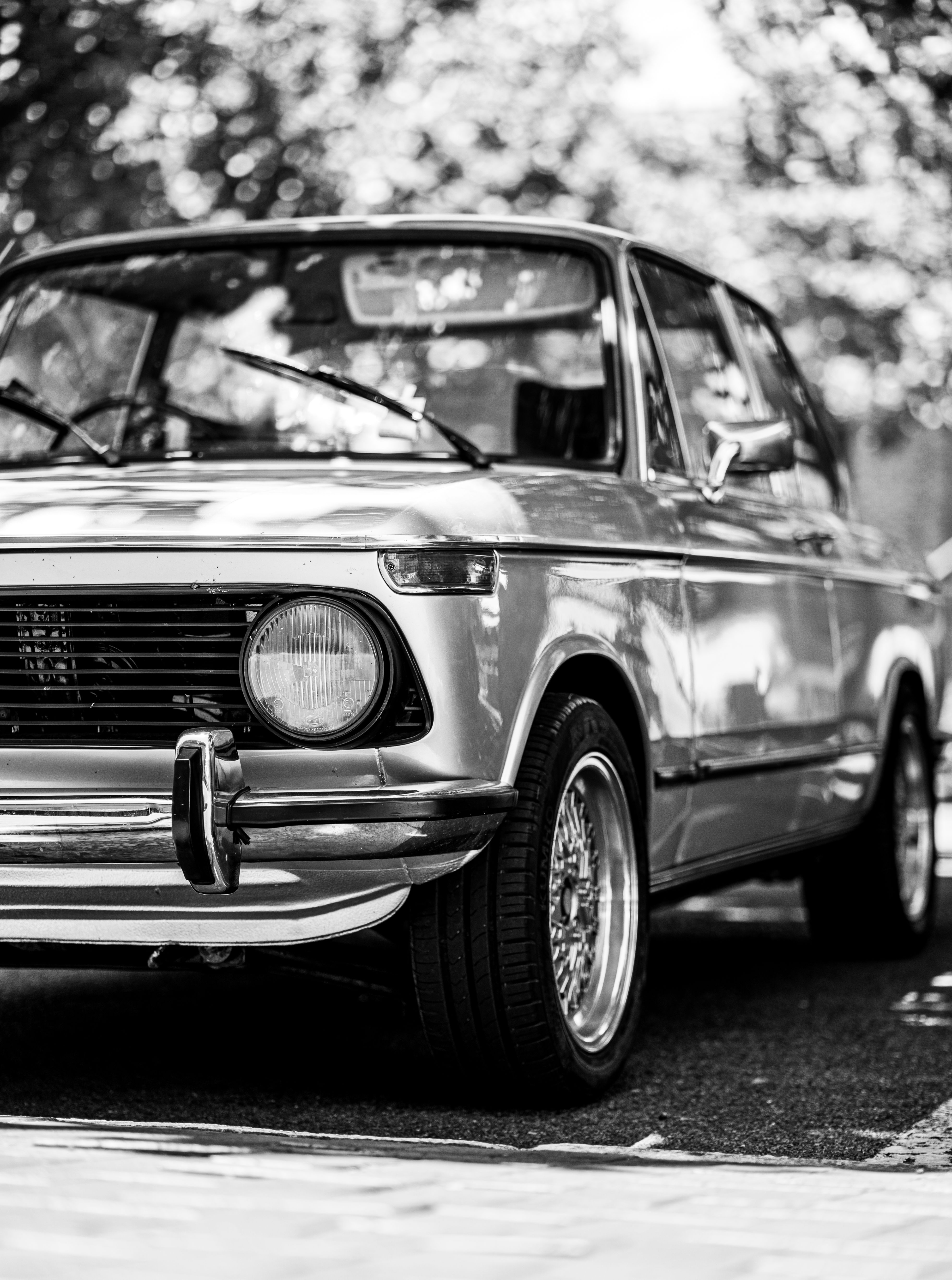 Grayscale Photo of a Classic Car Parked on Grass · Free Stock Photo