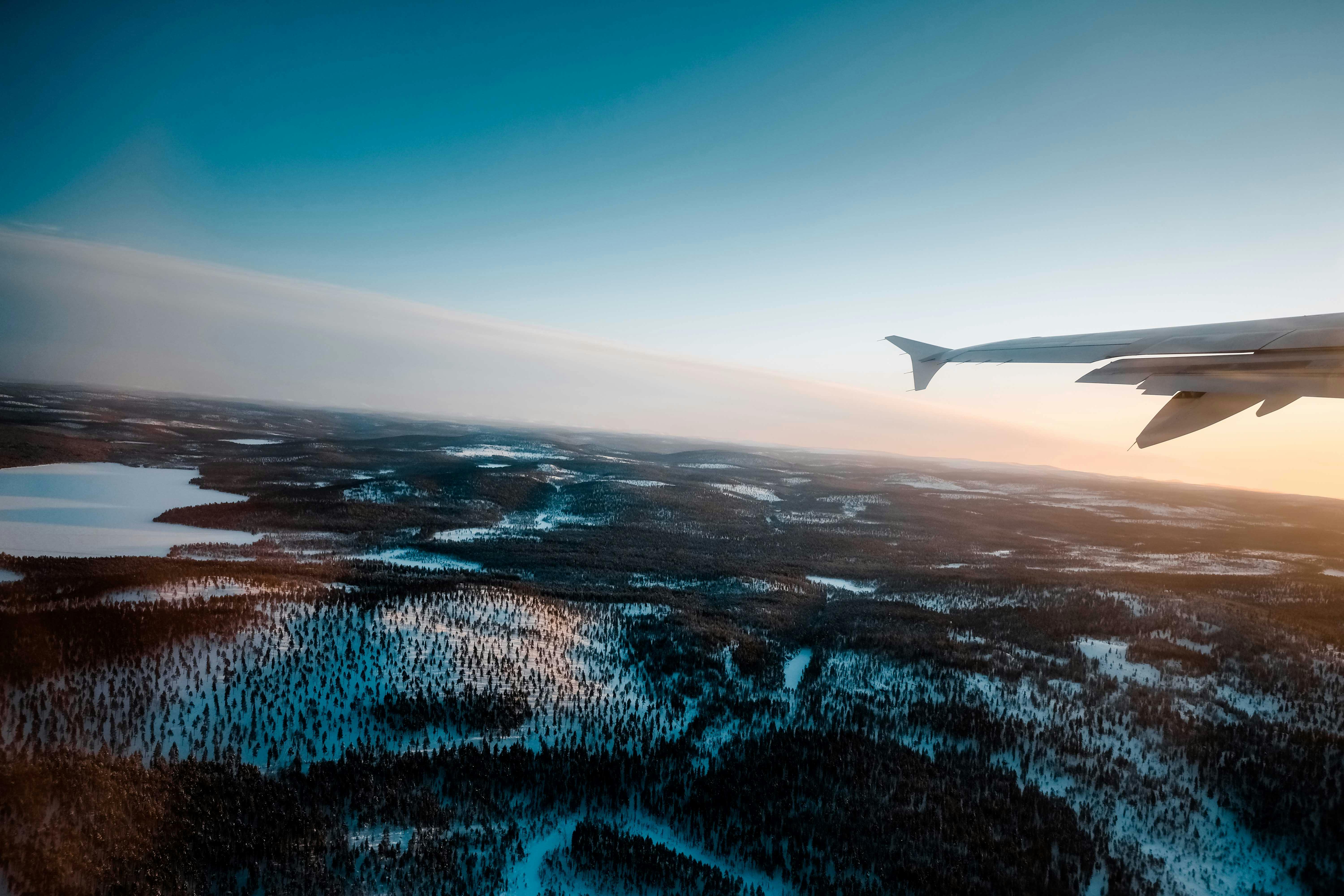 Aircraft flying over snowy forest in morning · Free Stock Photo