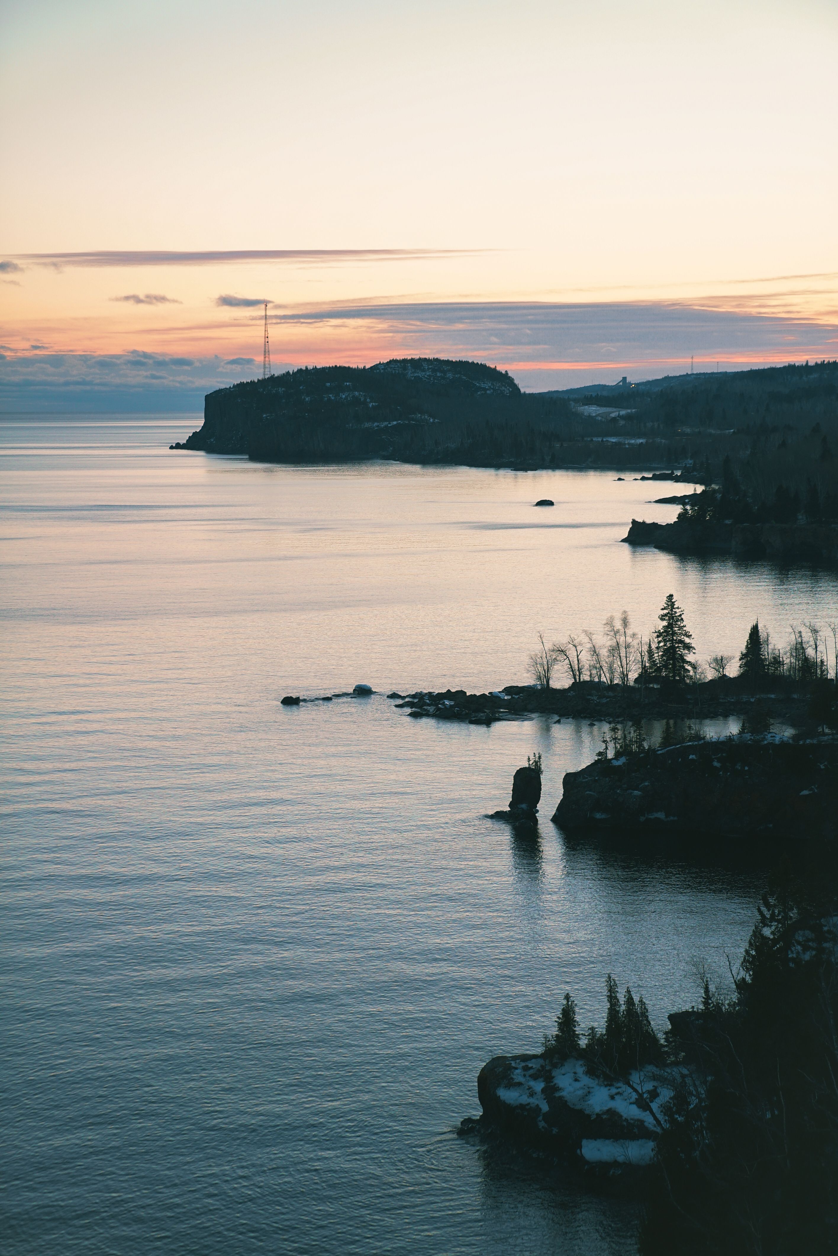 Rocky coastline of calm sea against sundown sky · Free Stock Photo