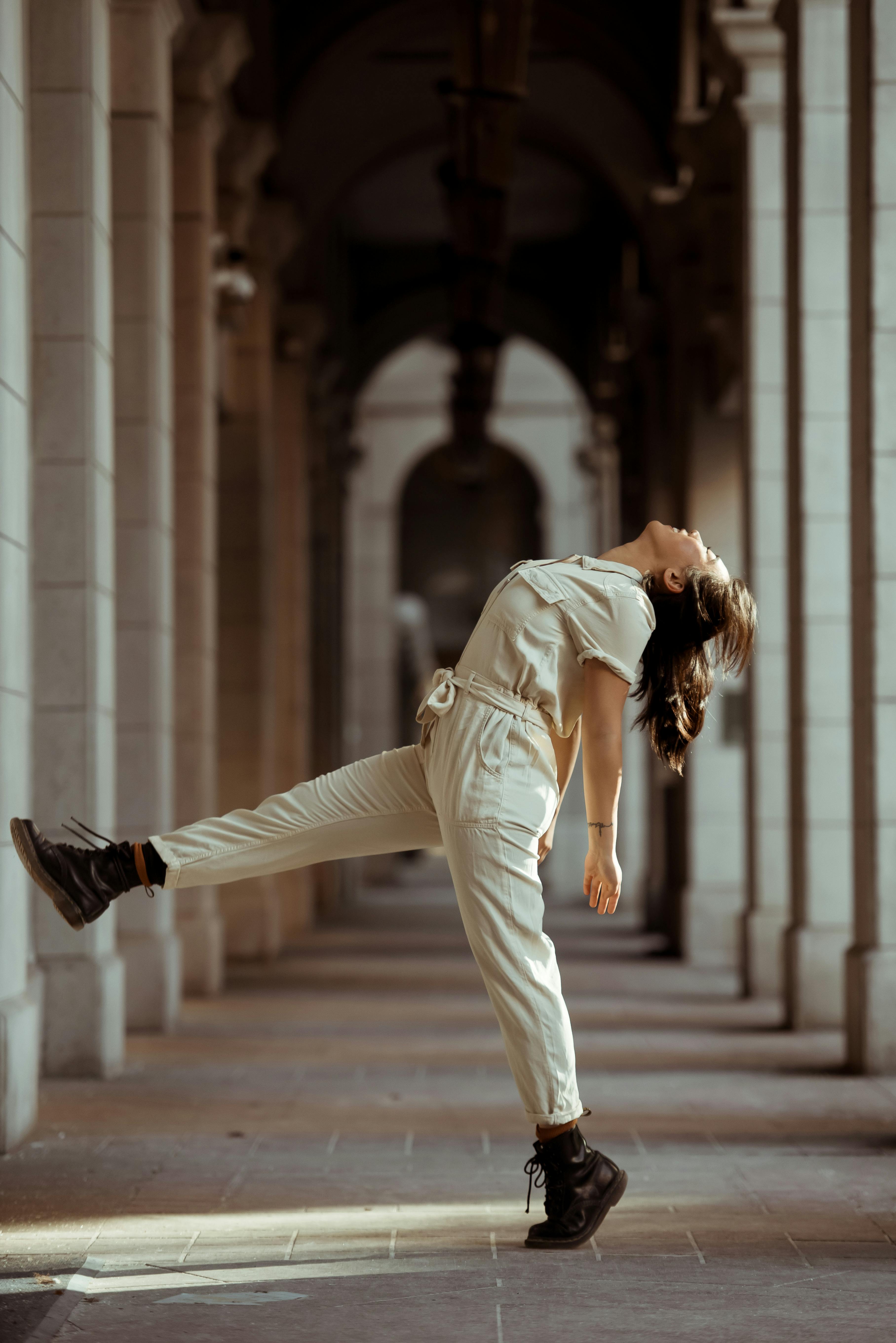 Woman standing on tiptoe in passage of colonnades · Free Stock Photo