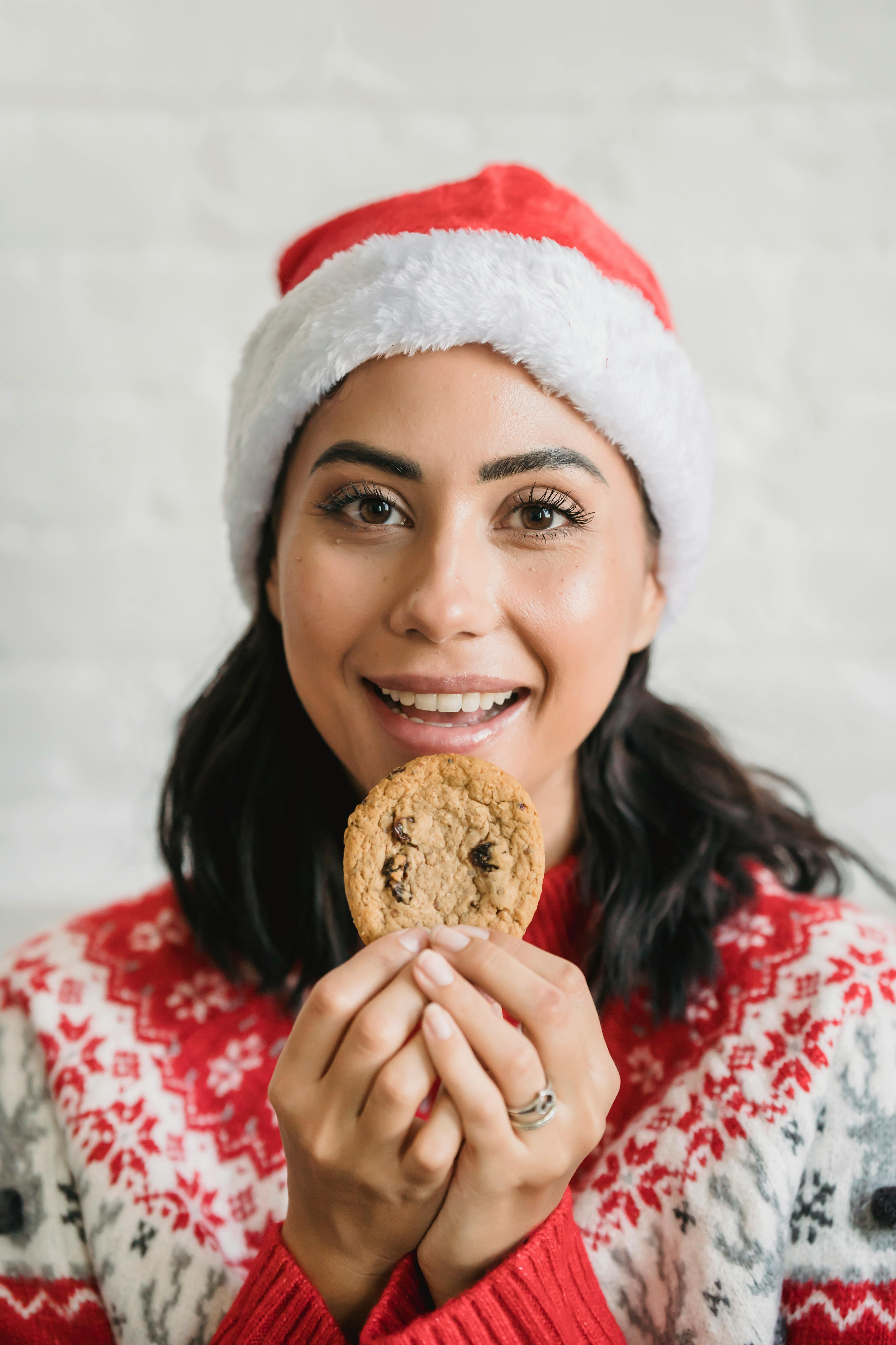 Smiling female with chocolate cookie looking at camera against brick ...