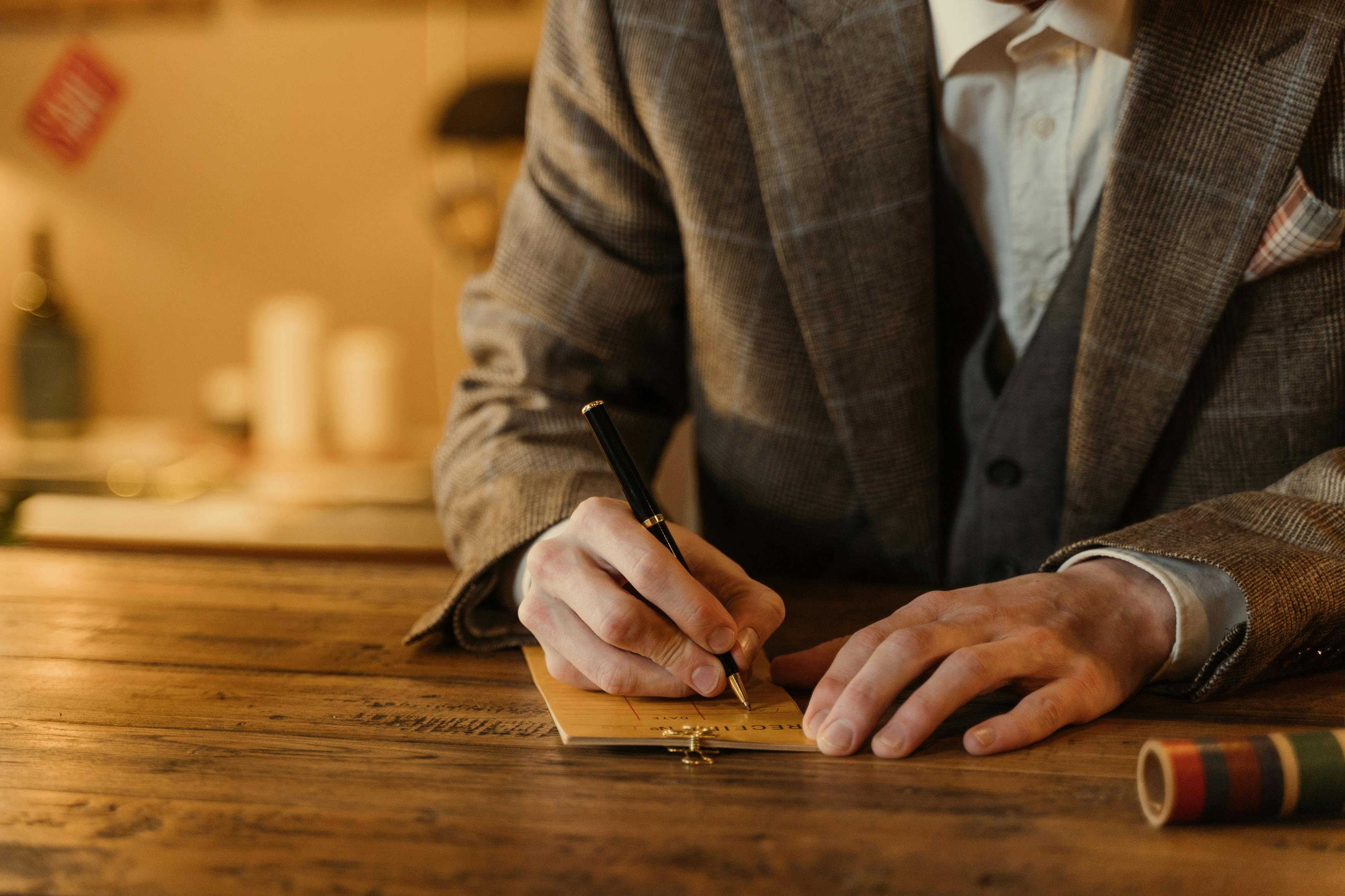 Person in Gray Suit Writing on a Paper · Free Stock Photo